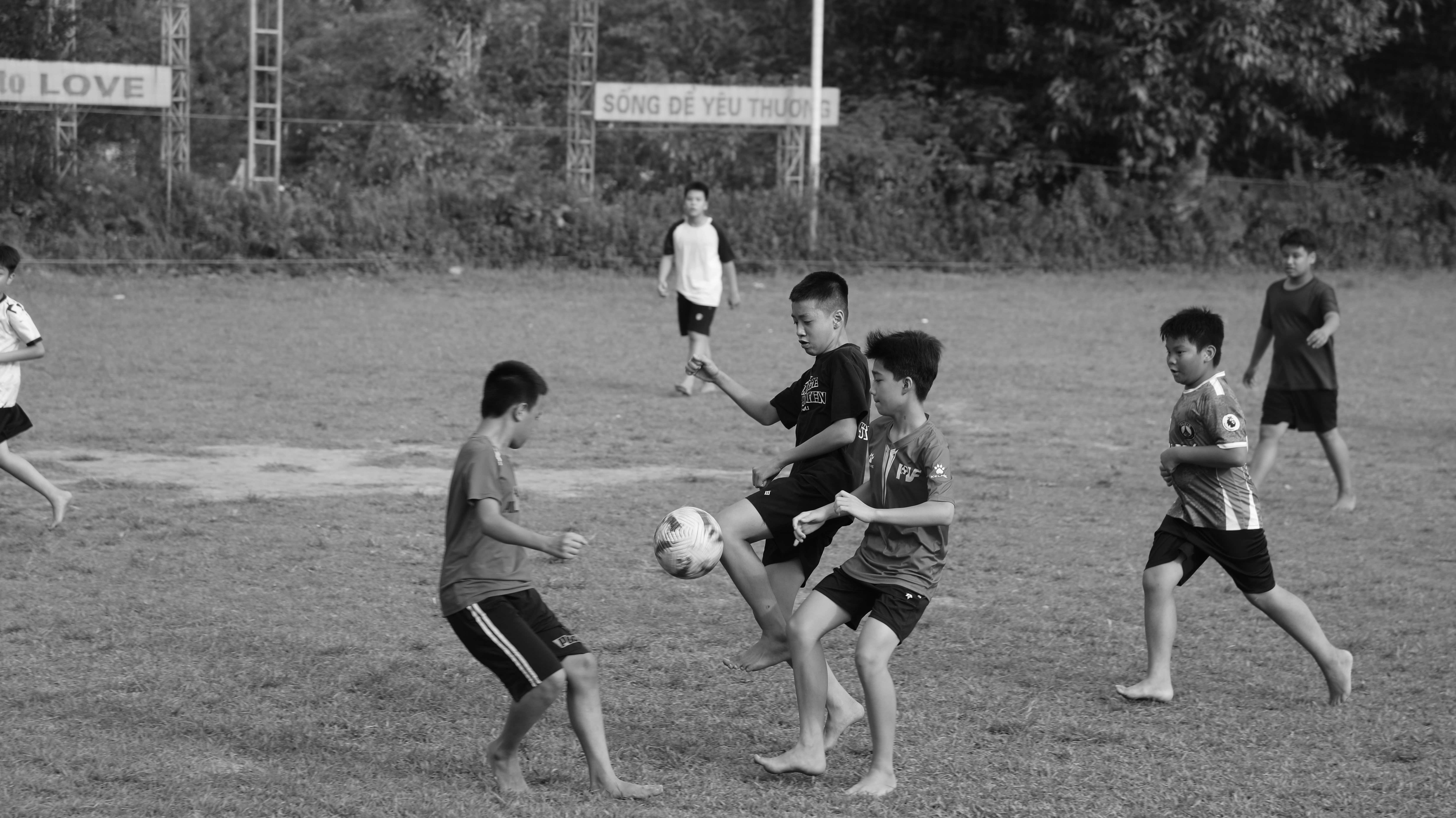 Midfield scramble: boys chase a soccer ball on a dusty field