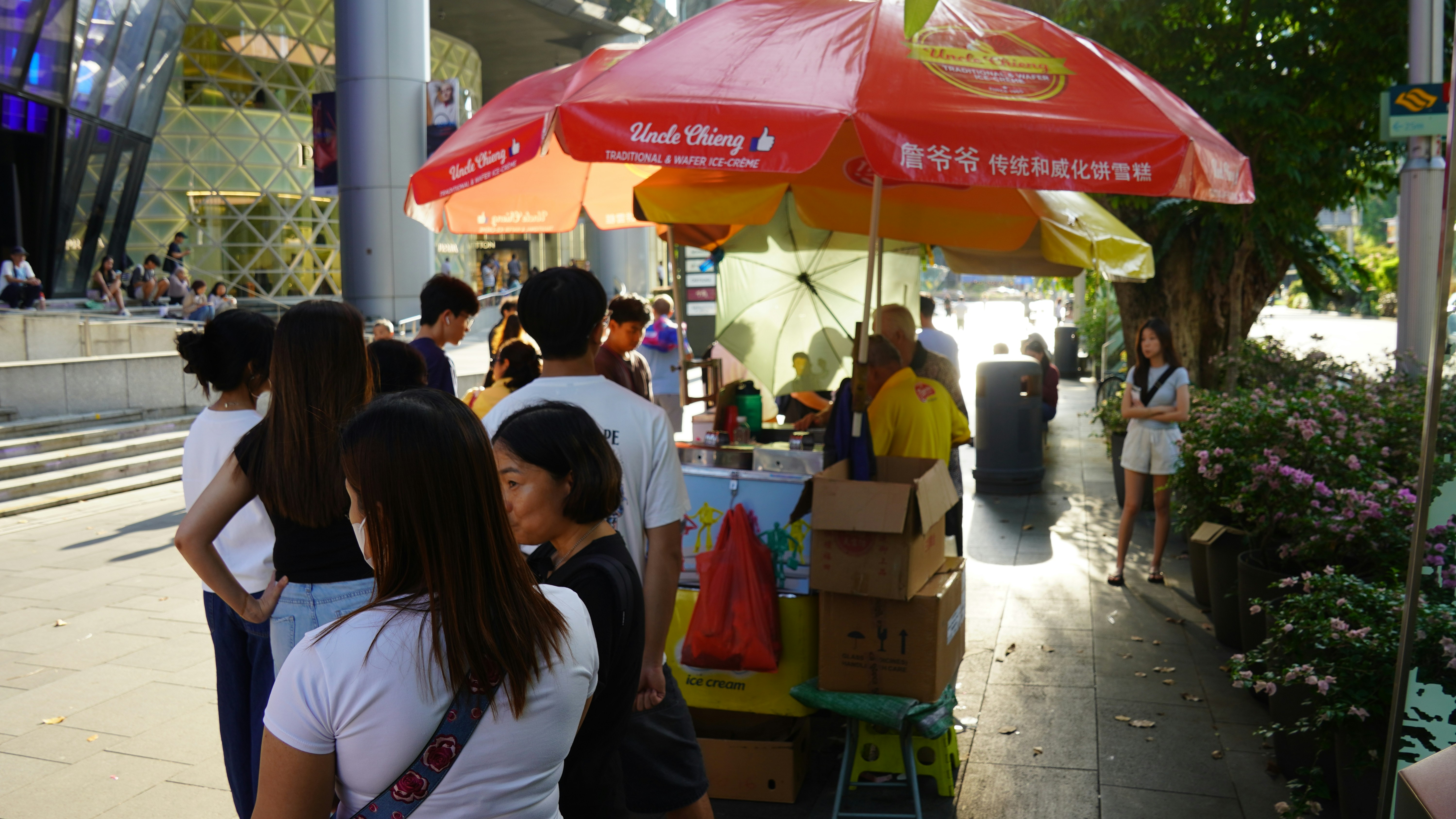 Crowd under market umbrellas at a sunny outdoor stall
