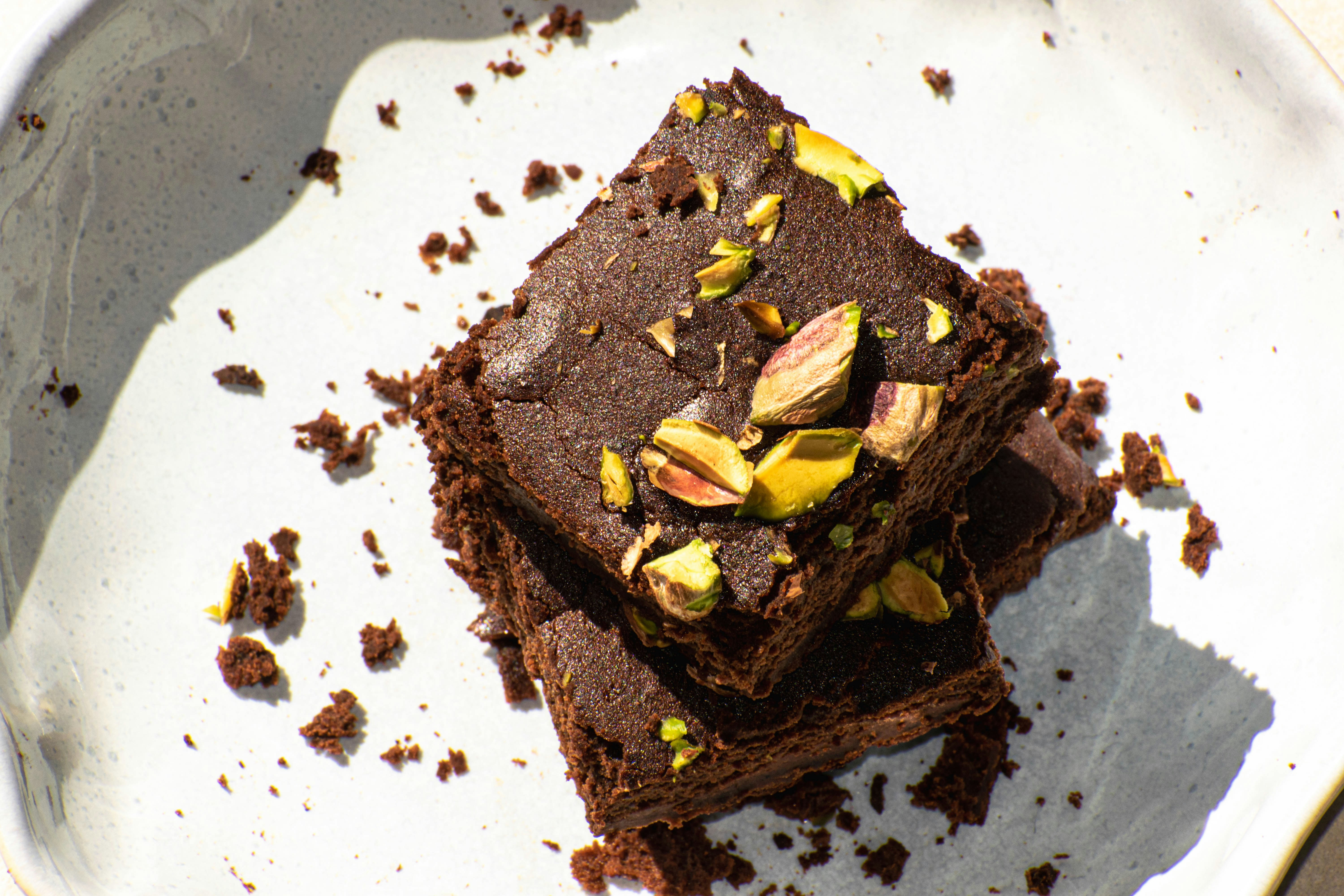 Pistachio-topped Chocolate brownies on a sunlit plate