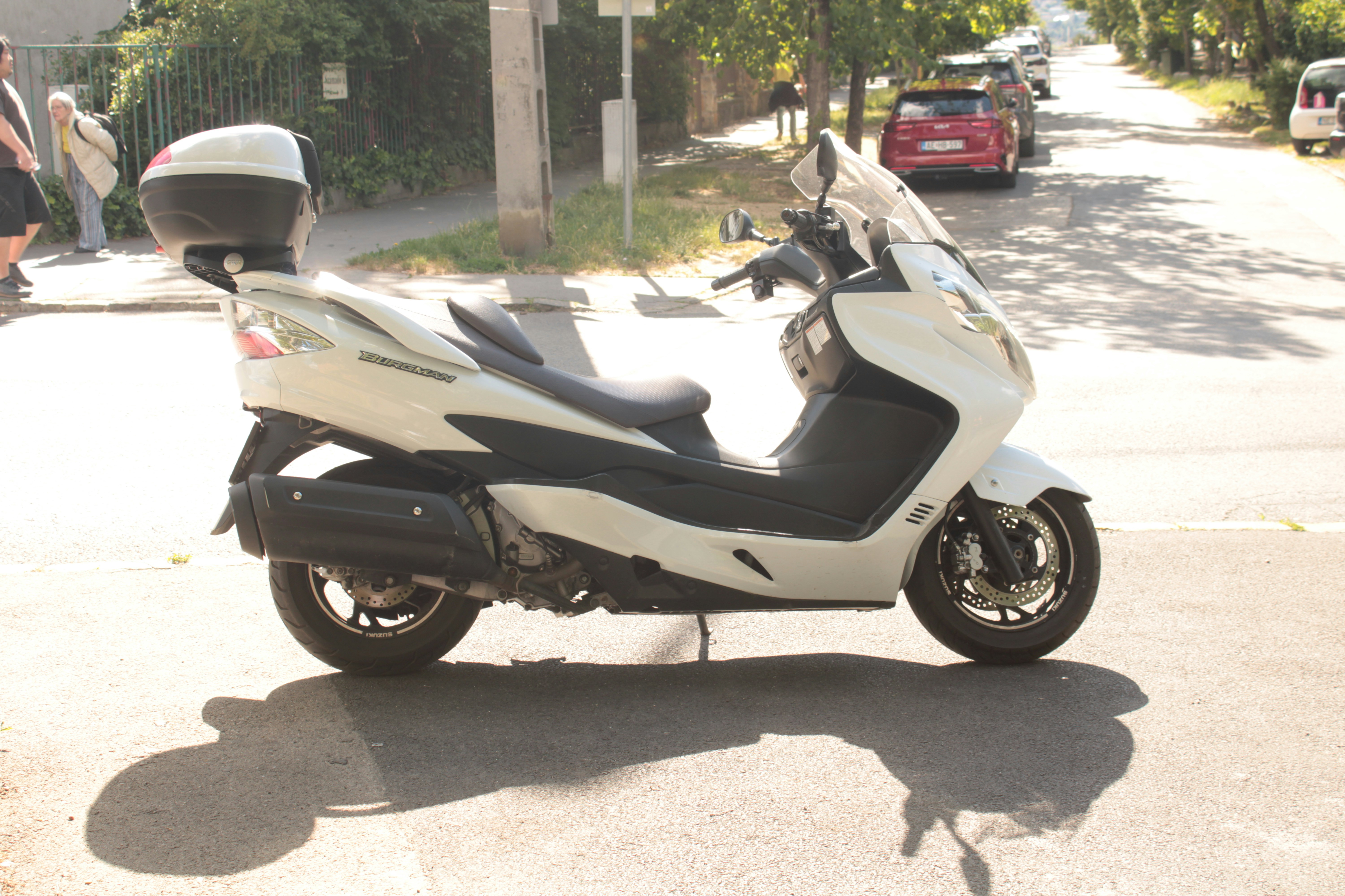 Cream-Colored Scooter Parked Under May Sun on Quiet Street