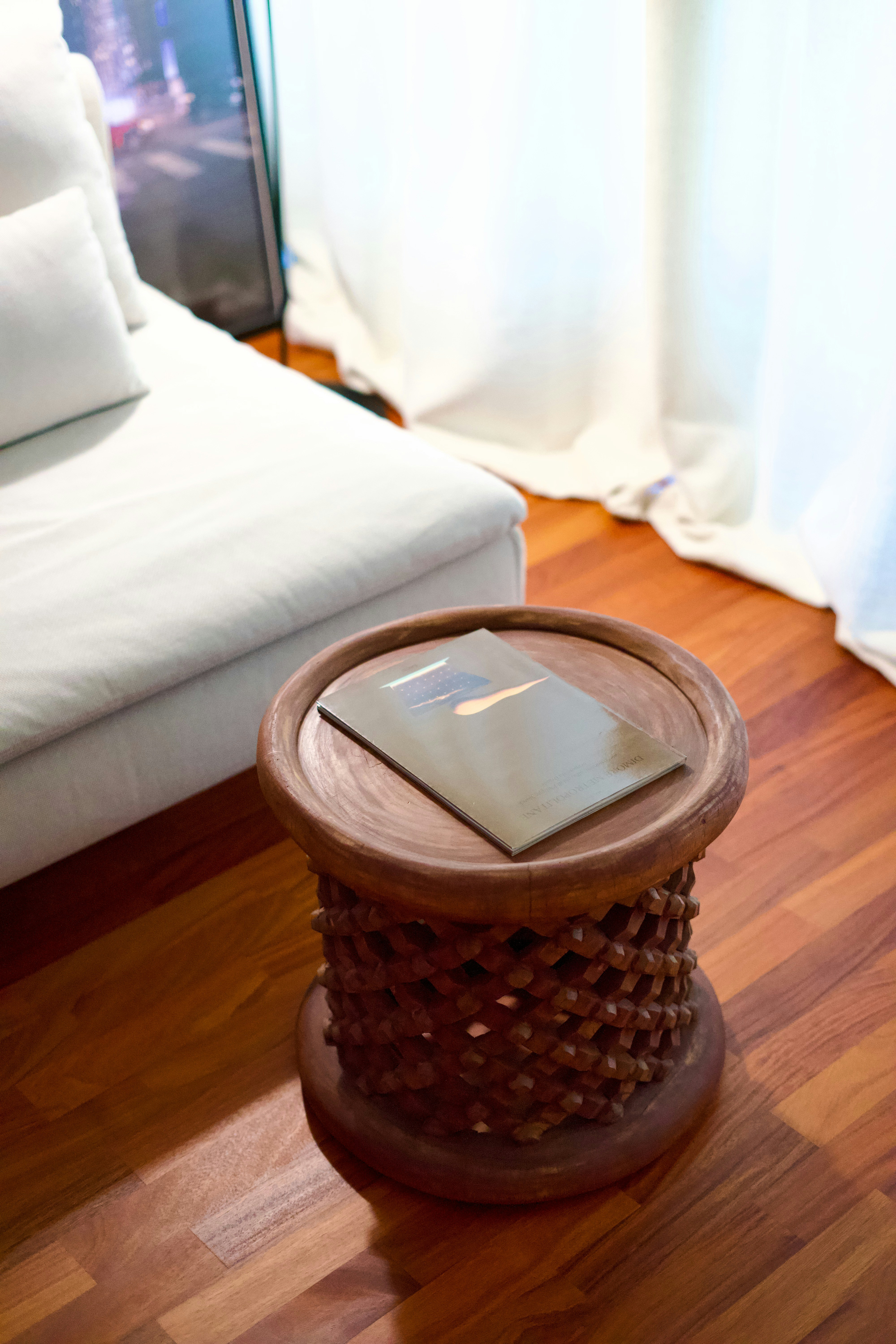 Wooden Nest: A Magazine rests on a woven side table beside a white sofa