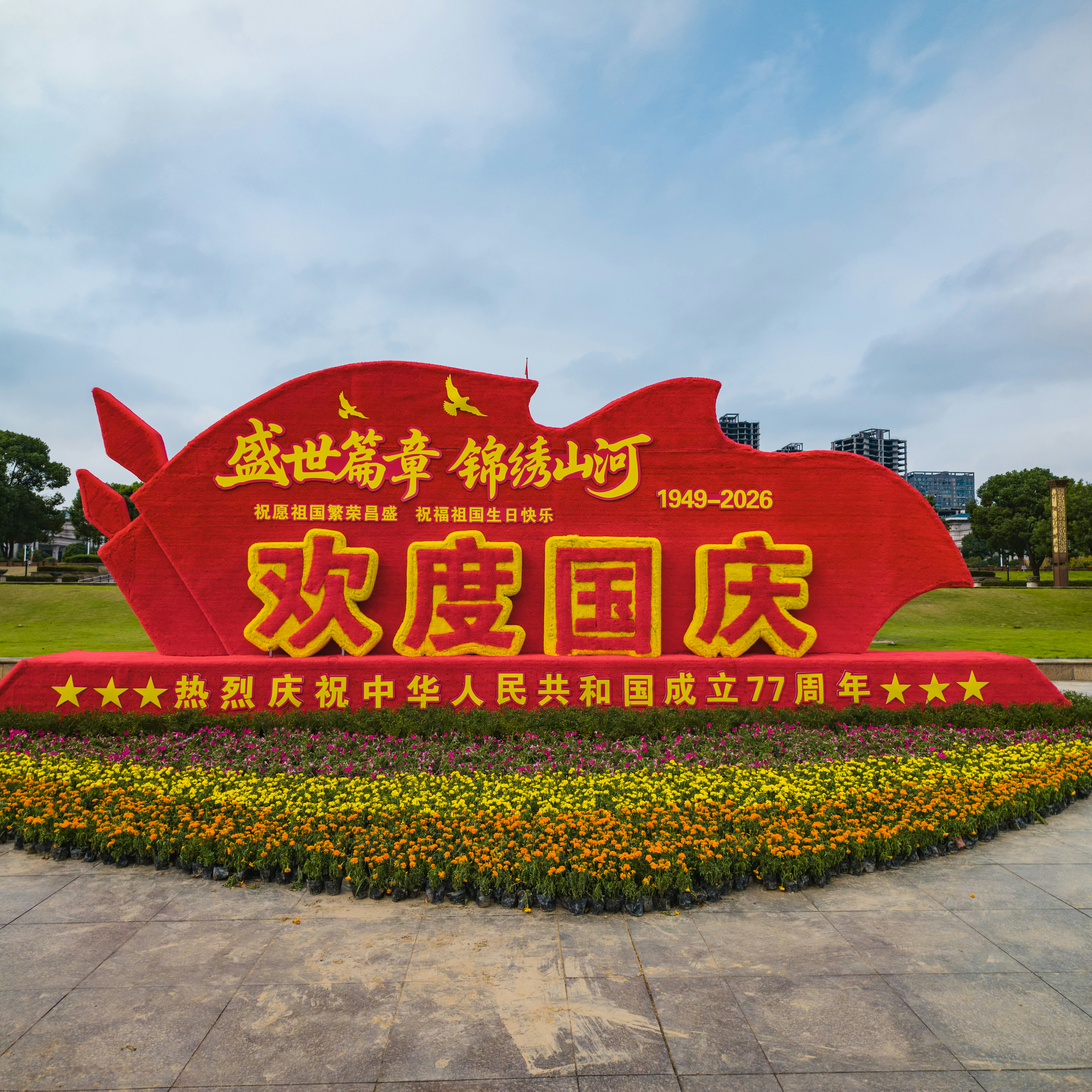 Red Monument Celebrating National Day Surrounded by Flower Beds