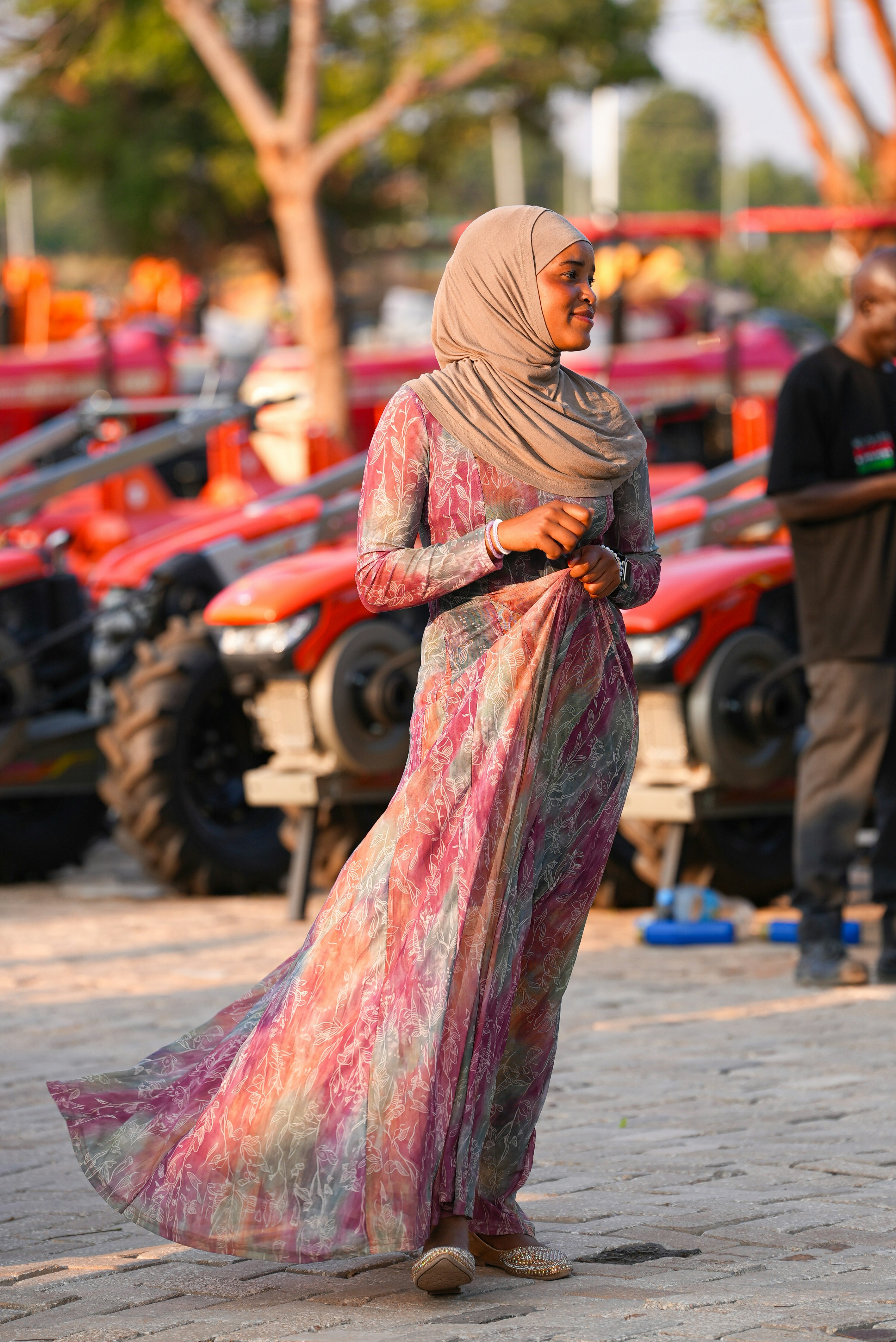 Grace in Motion: A Modest Dress Flows as a Woman Walks Among Machinery