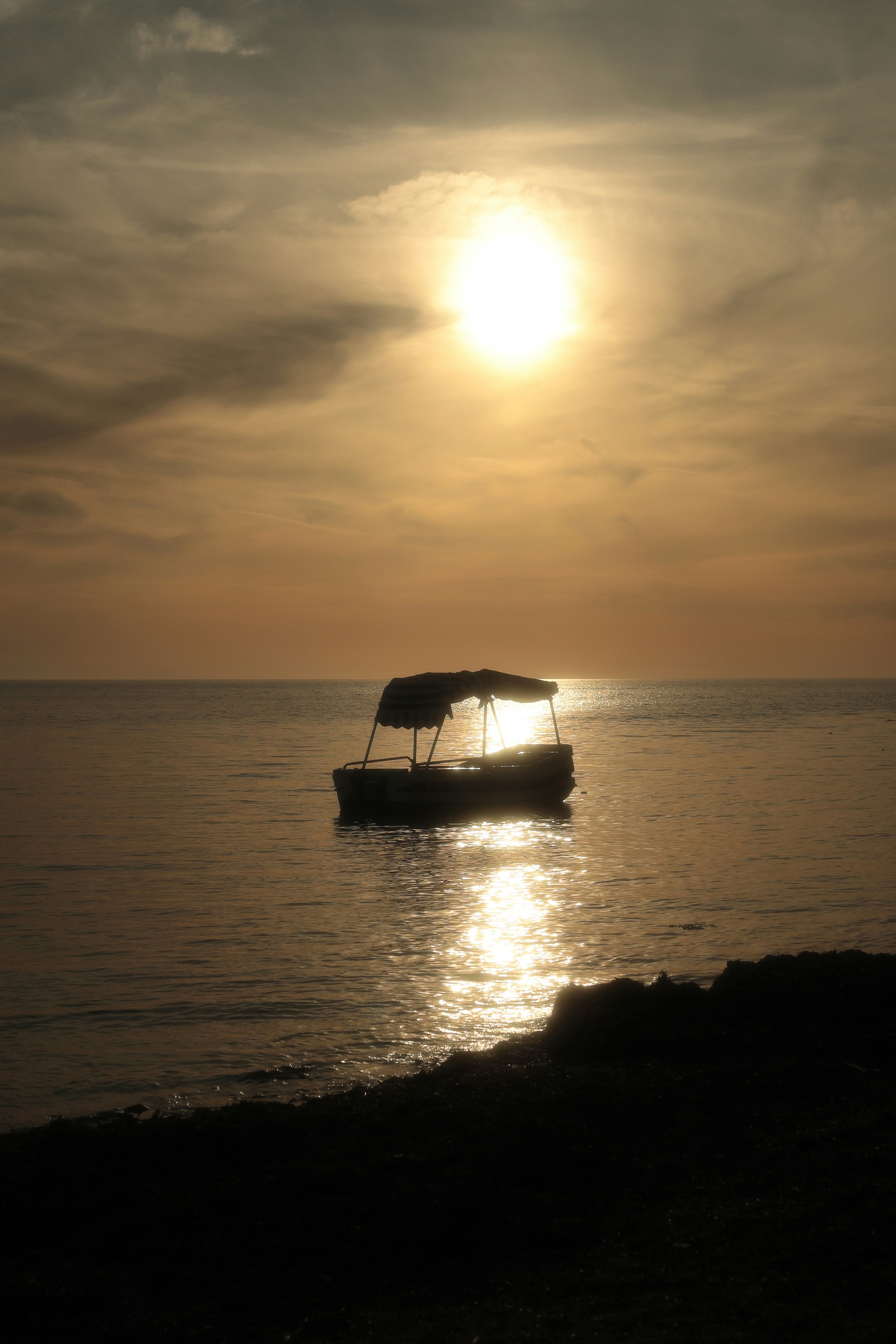 Silhouette at Sunset: A Boat Drifts in Golden Light