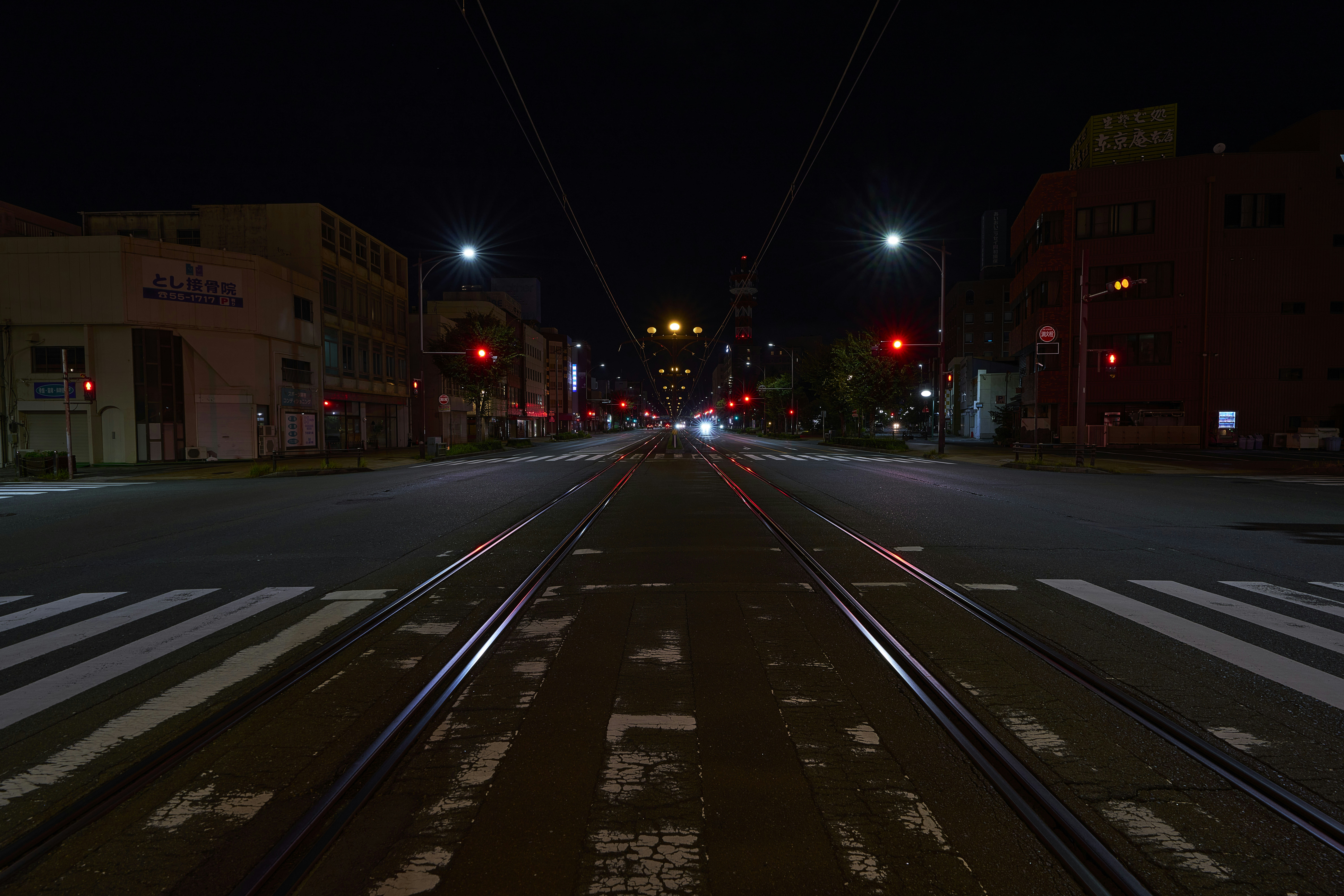 Night Streetcar Rails Converge under Neon Constellations
