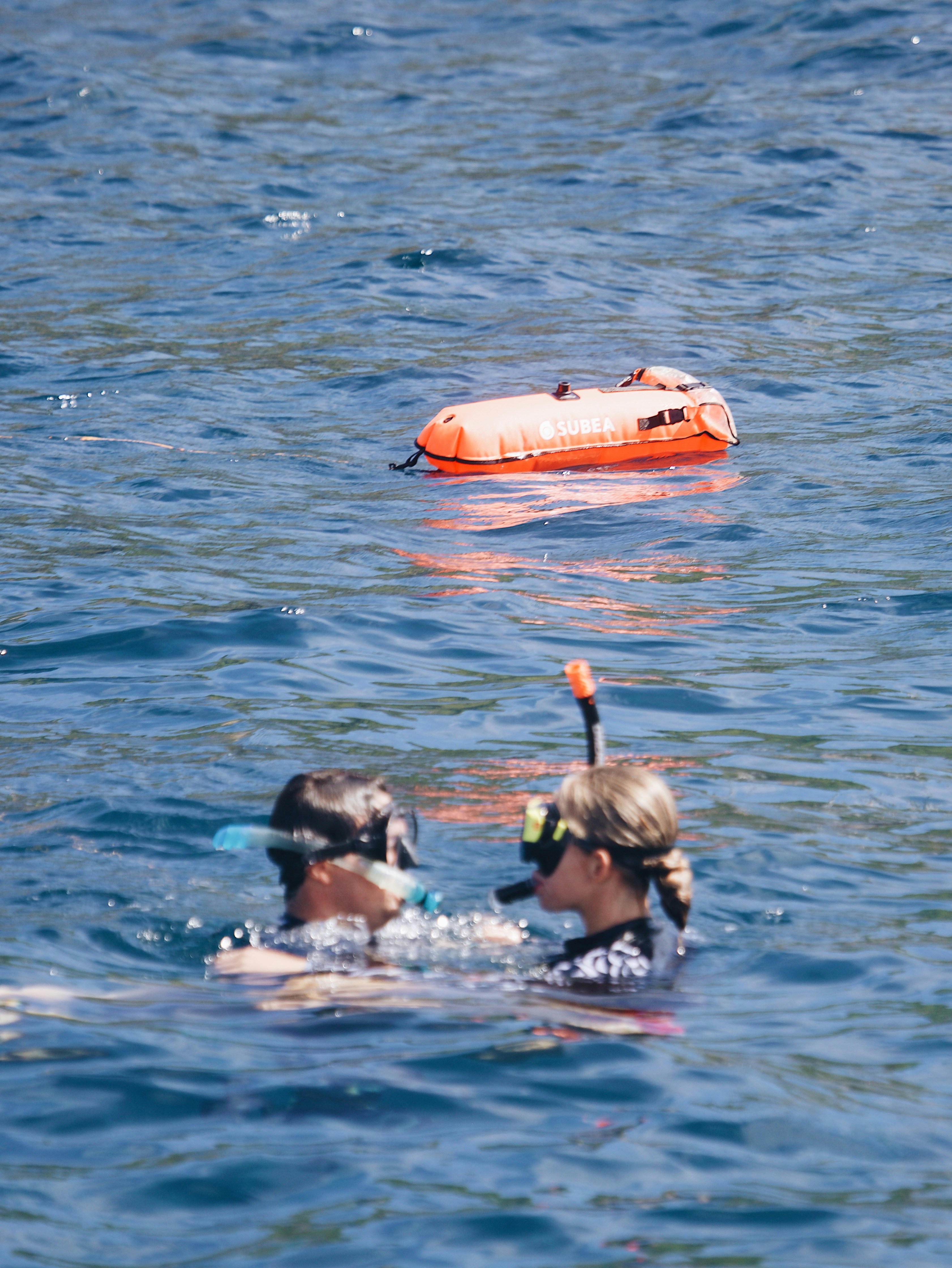 Floating orange lifebuoy Drifts Above Coral-Blue Quiet Sea