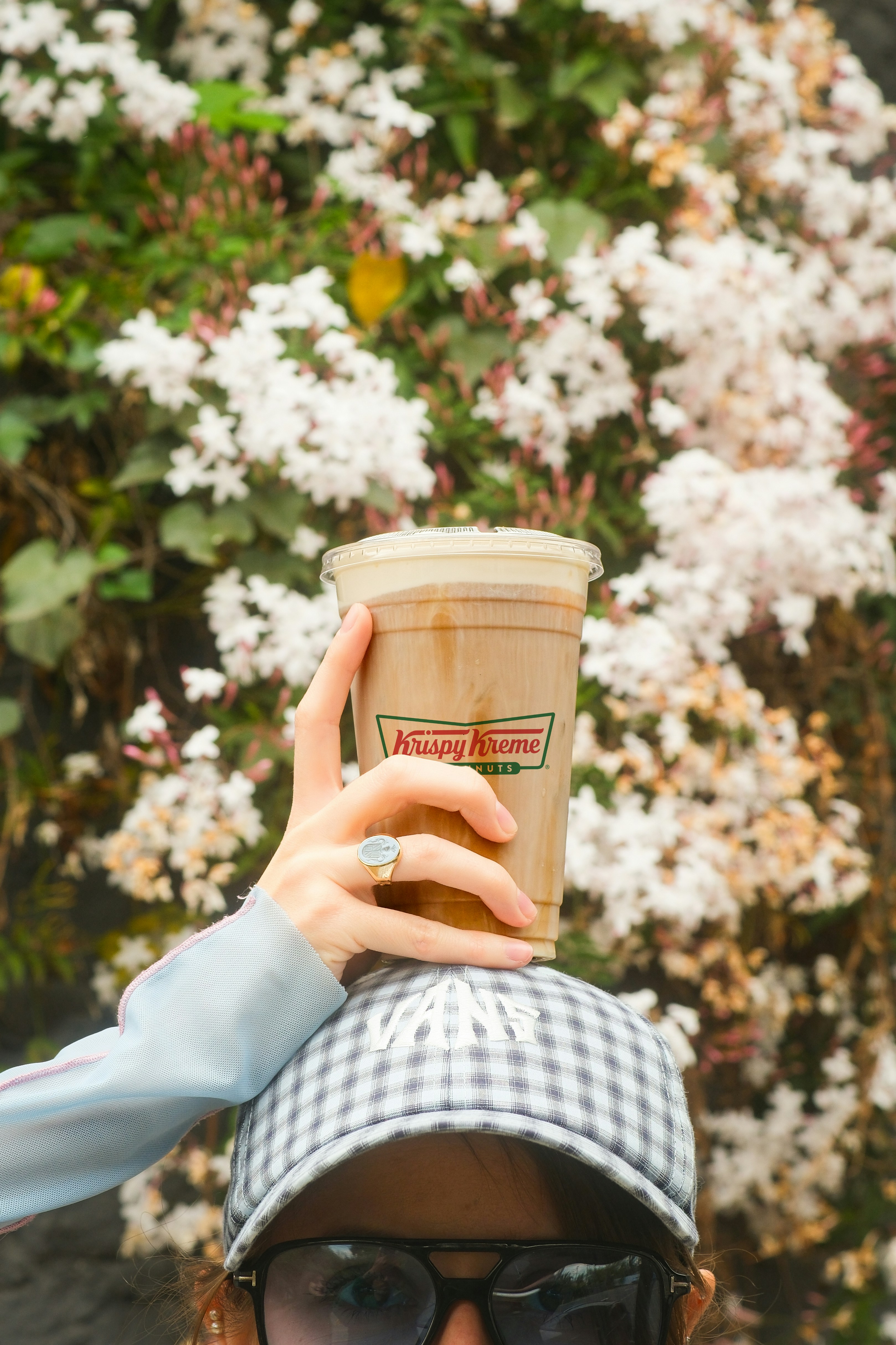 Krispy Glow: Coffee Cup Held Above a Floral Backdrop