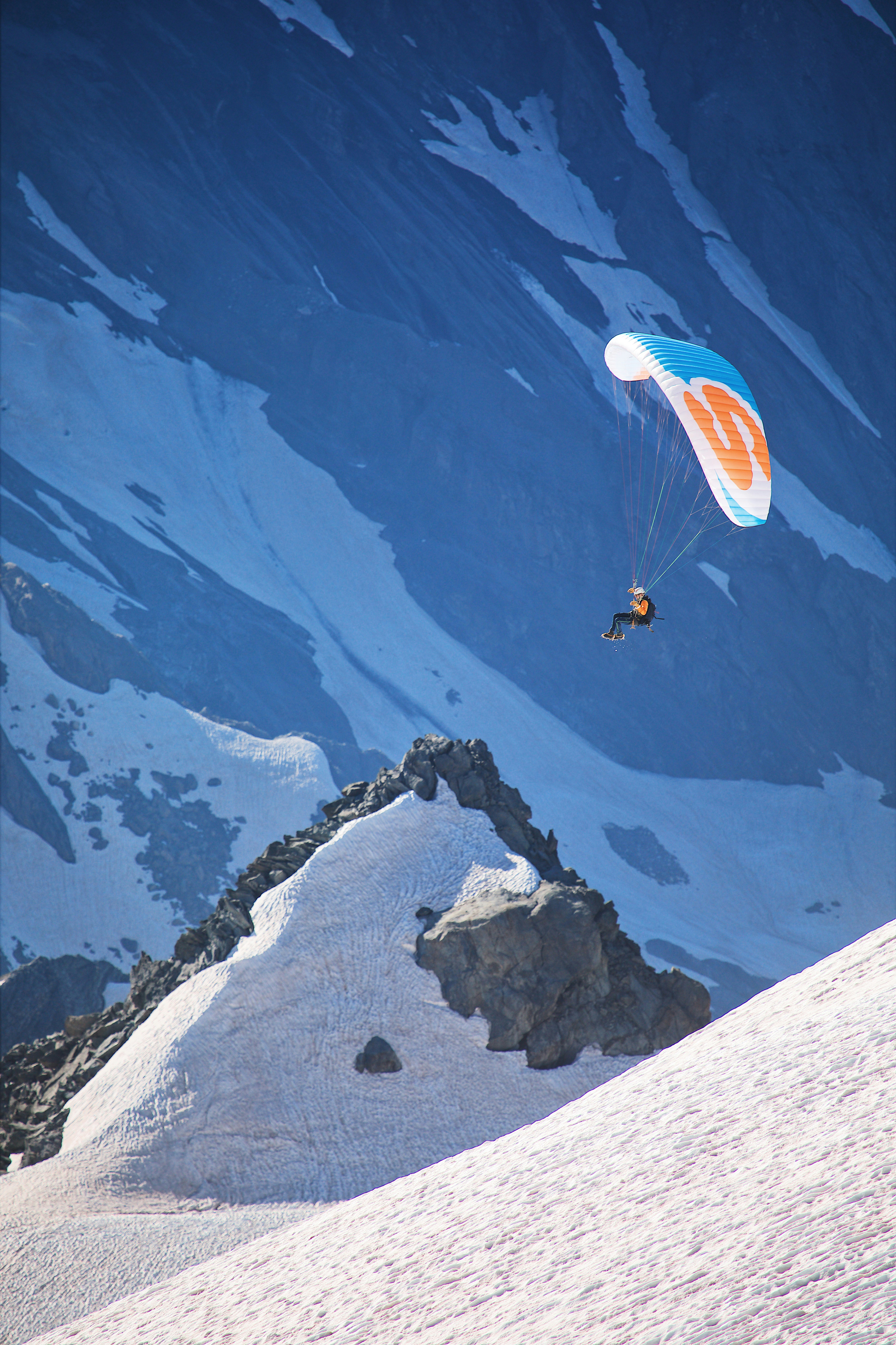 High-Altitude Glide: A Paraglider Against A Rugged Snow-Spine