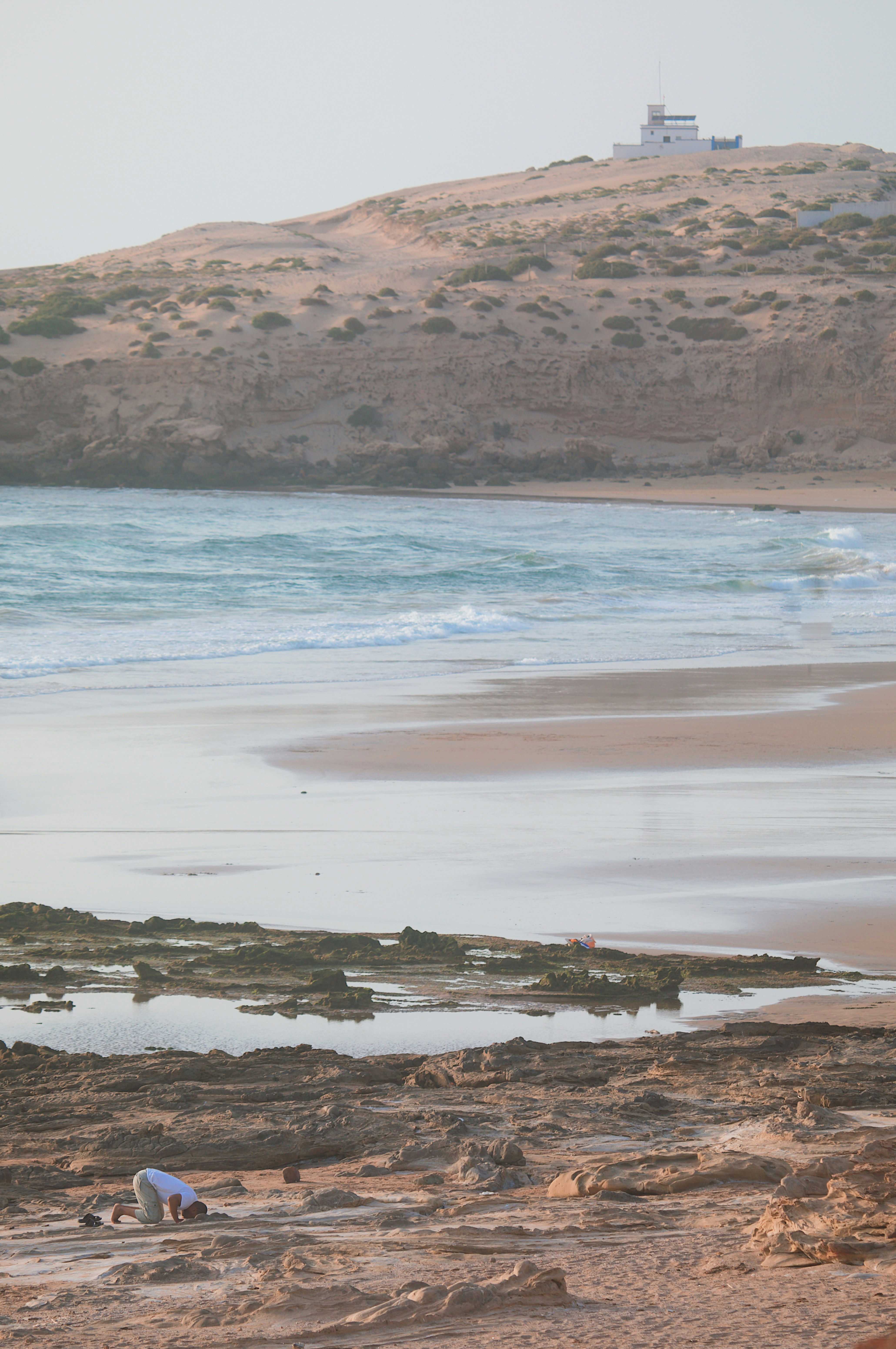 Coastal Quiet: A Lone Figure in the Tidal Bed Beneath Desert Hills