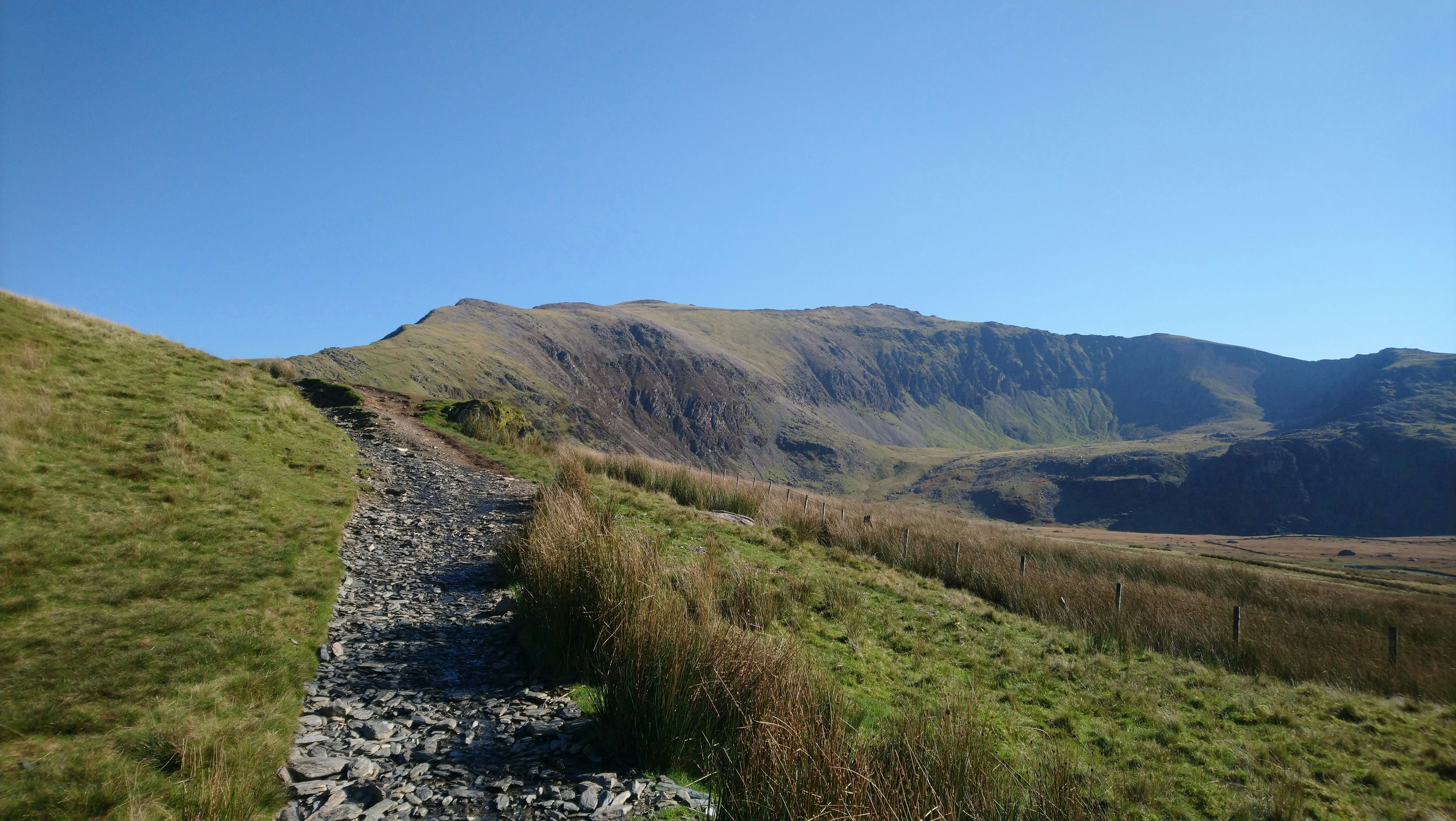 Stony trail winding toward a sunlit ridge under a cobalt sky