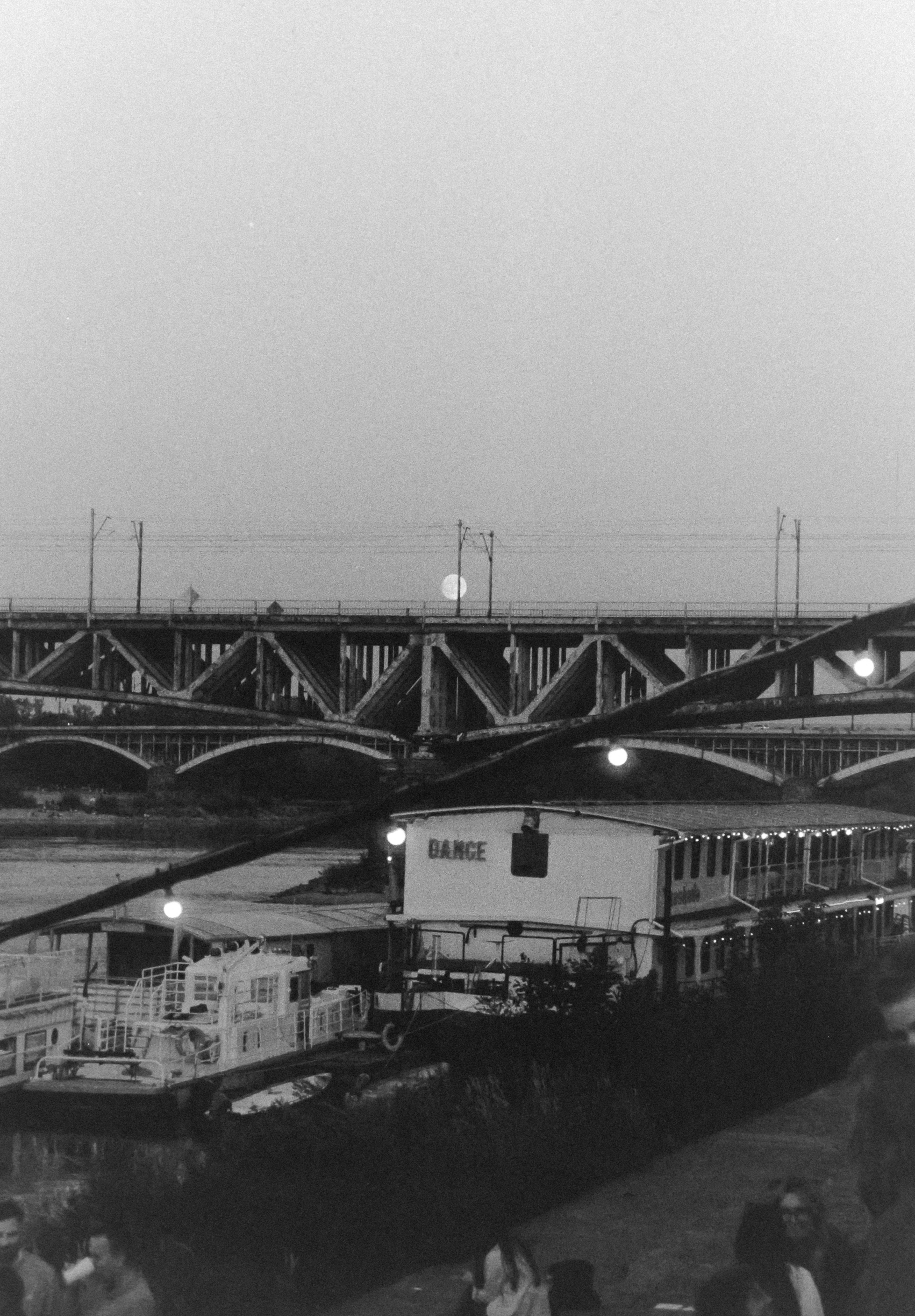 A river boat named Bange moored beneath a large bridge at night