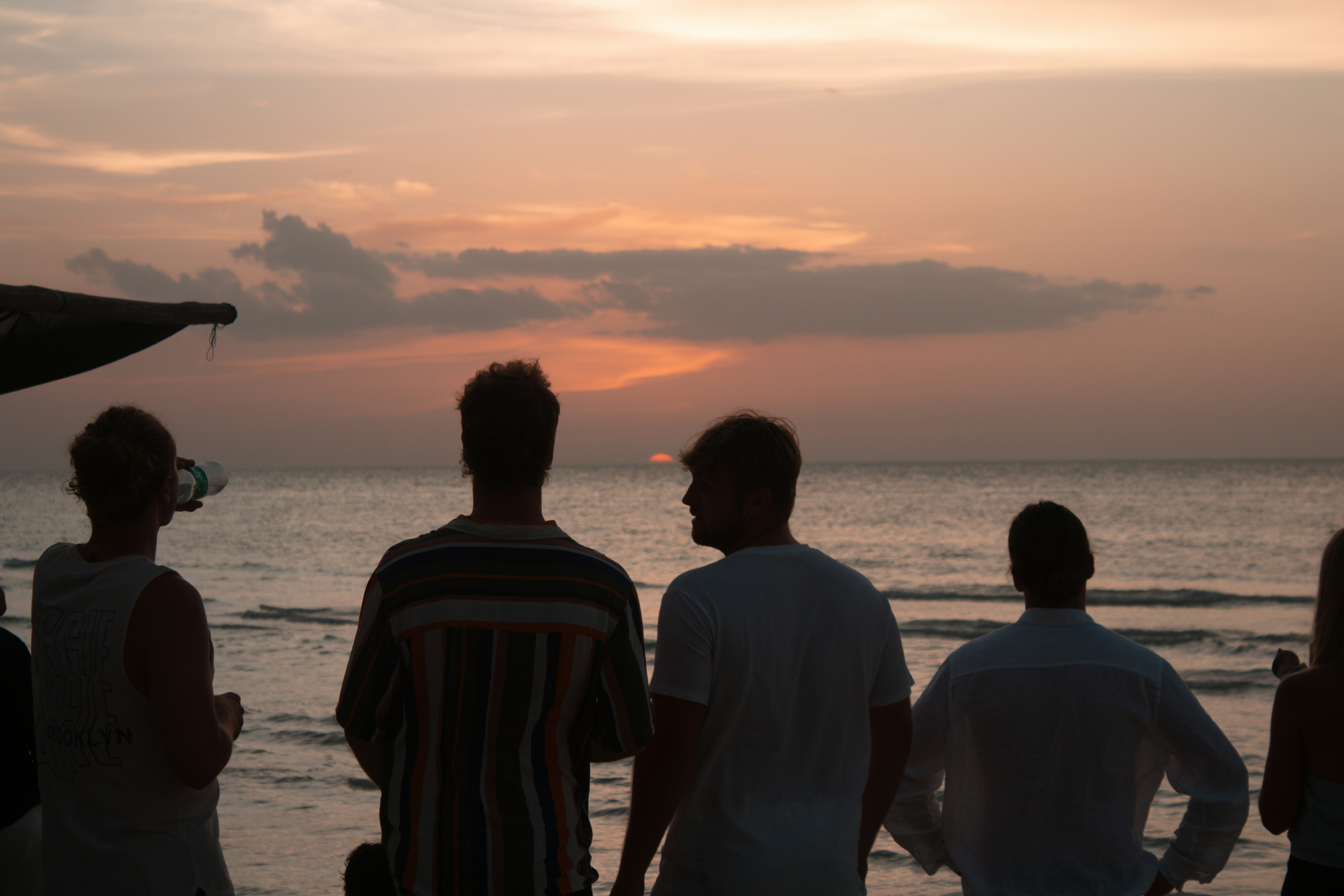 Sunset Silhouette: Friends Gaze Toward a Quiet Sea