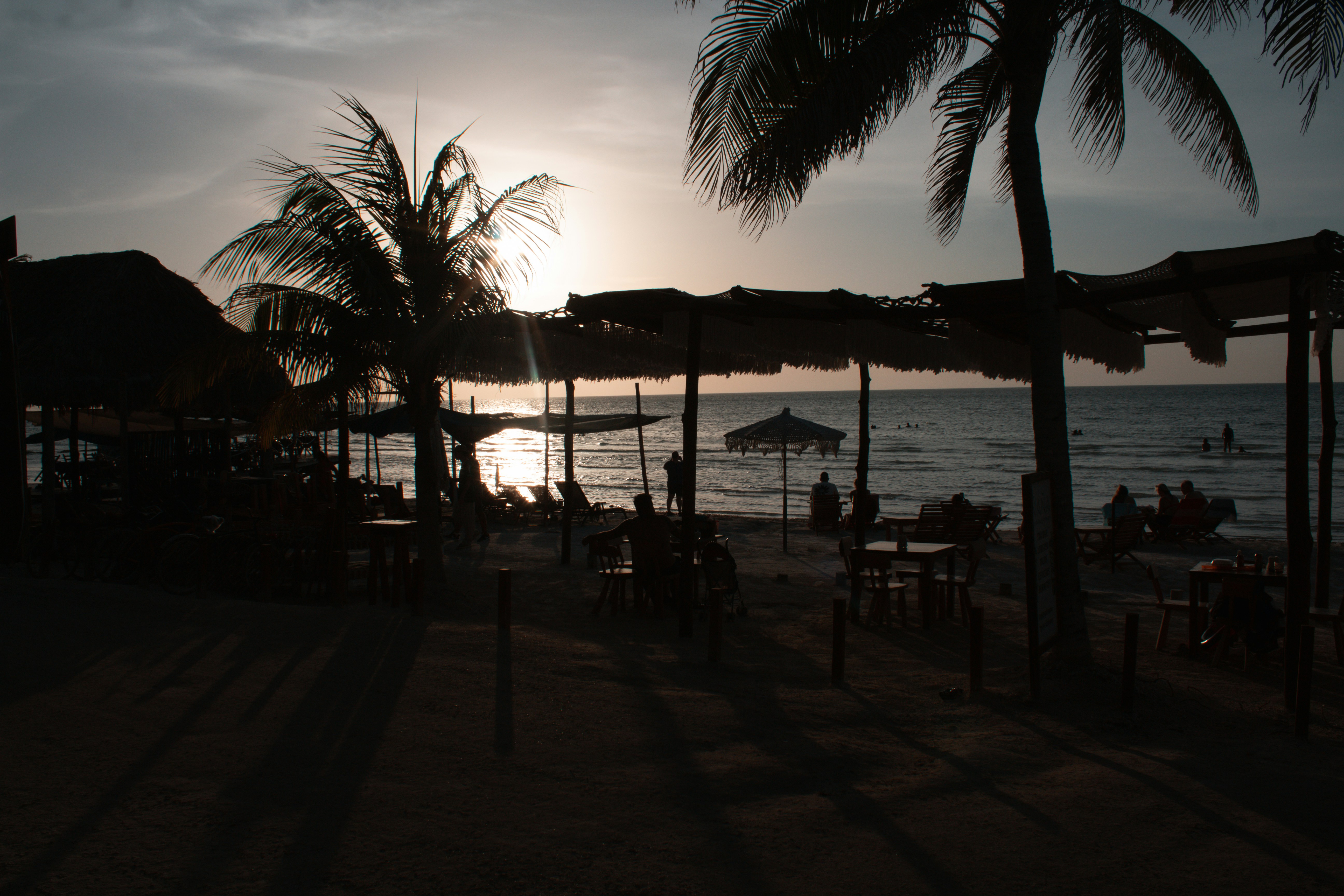Dusk at the Beach: Silhouettes Under Tarped Shade