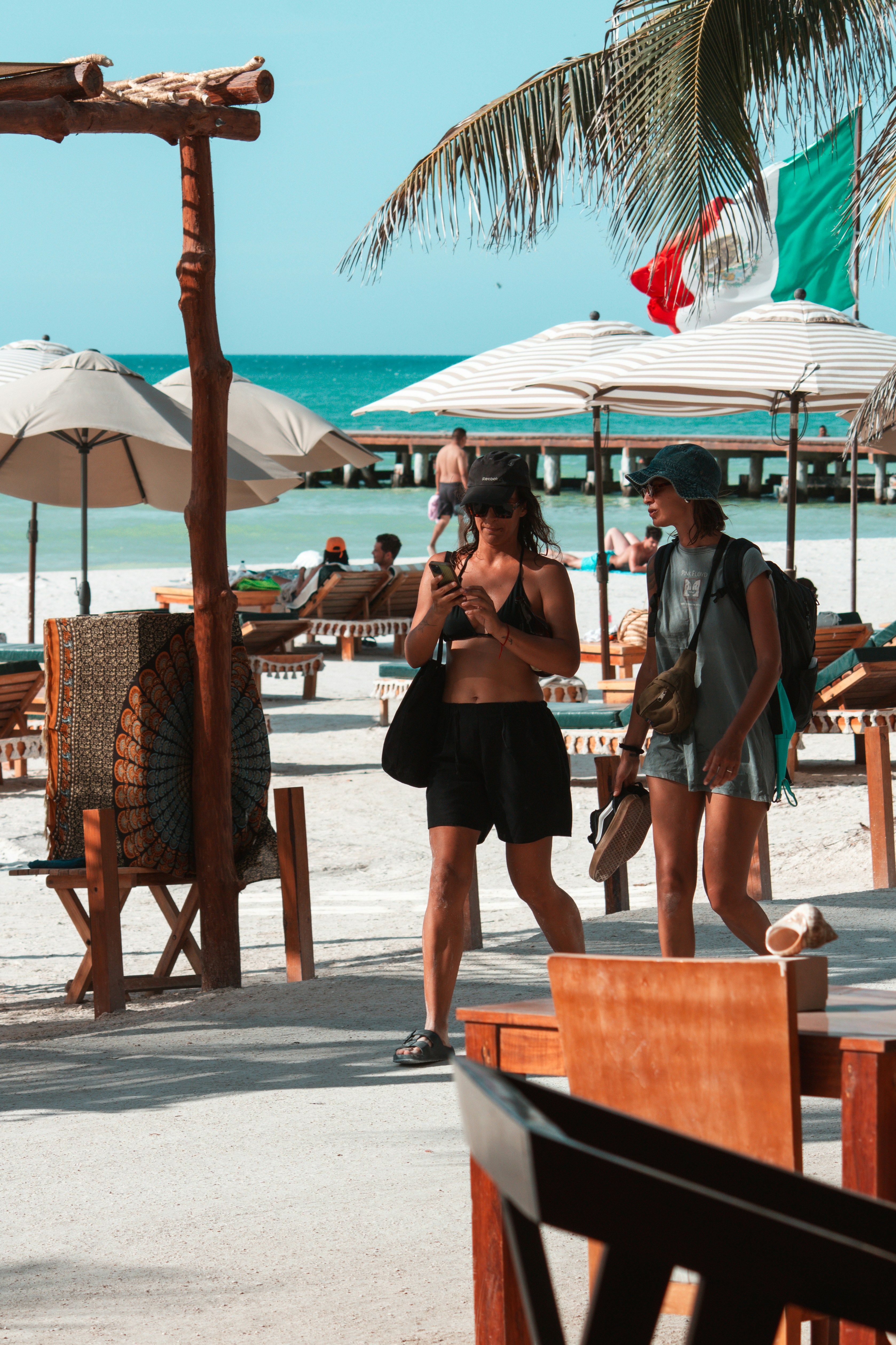 Sunlit Beach Stroll: Two Friends at a Tropical Shore