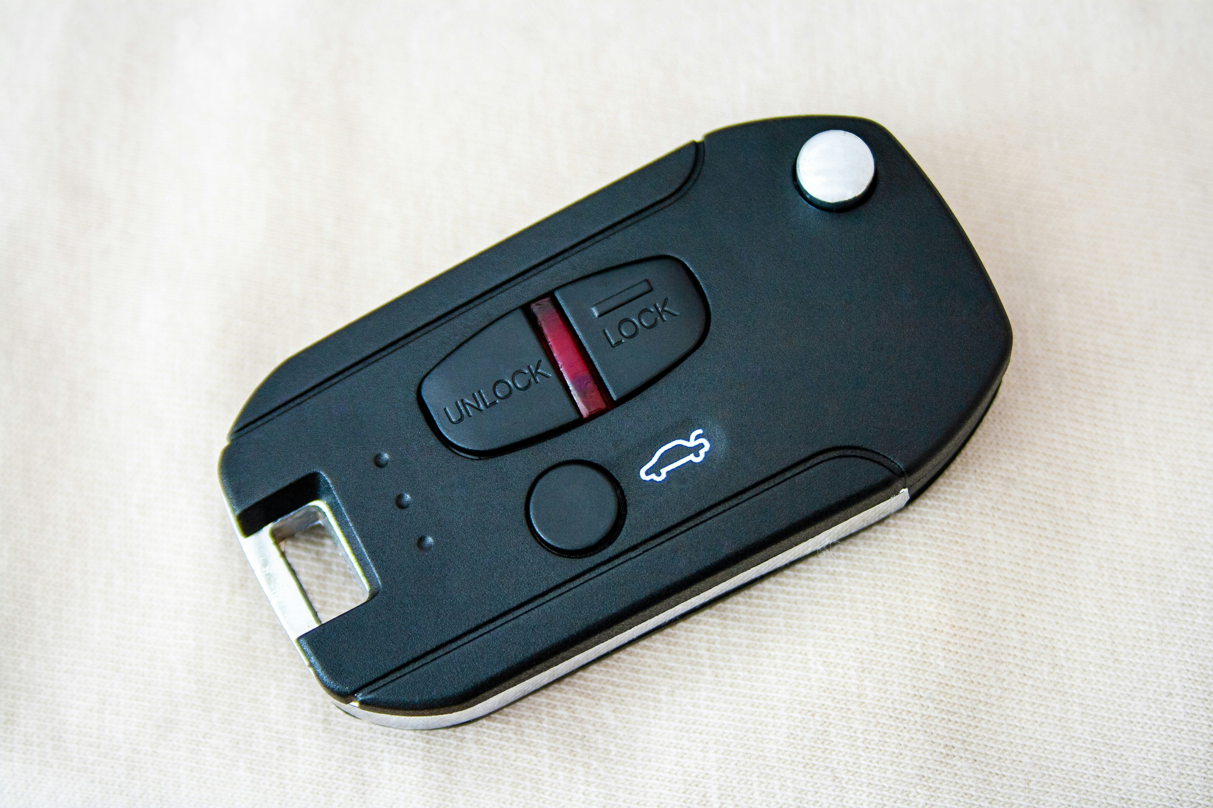 Top view of a black folding remote car key fob with lock, unlock, and trunk release buttons