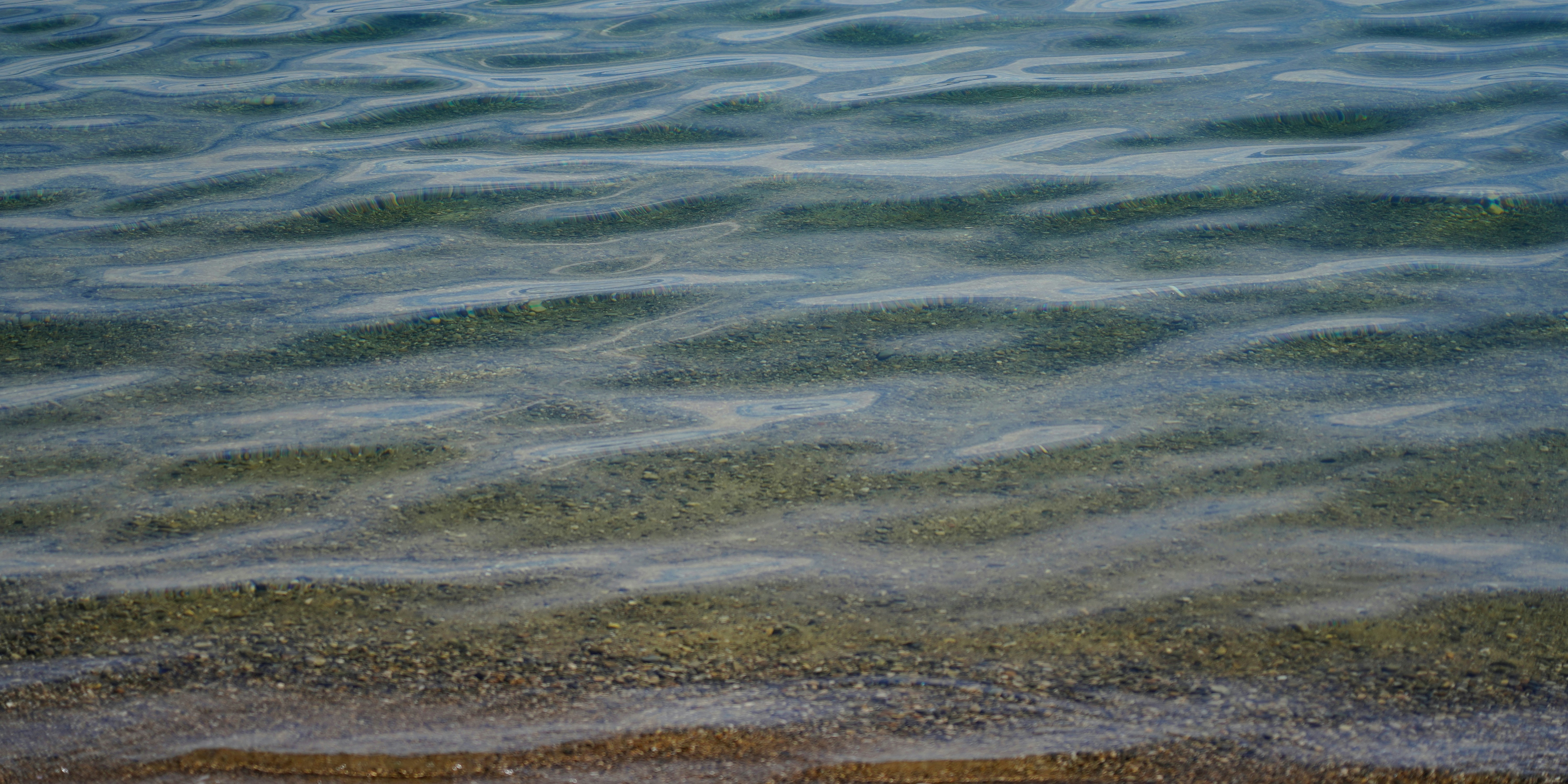 Rippling shallows: crystal-clear shoreline under a calm horizon