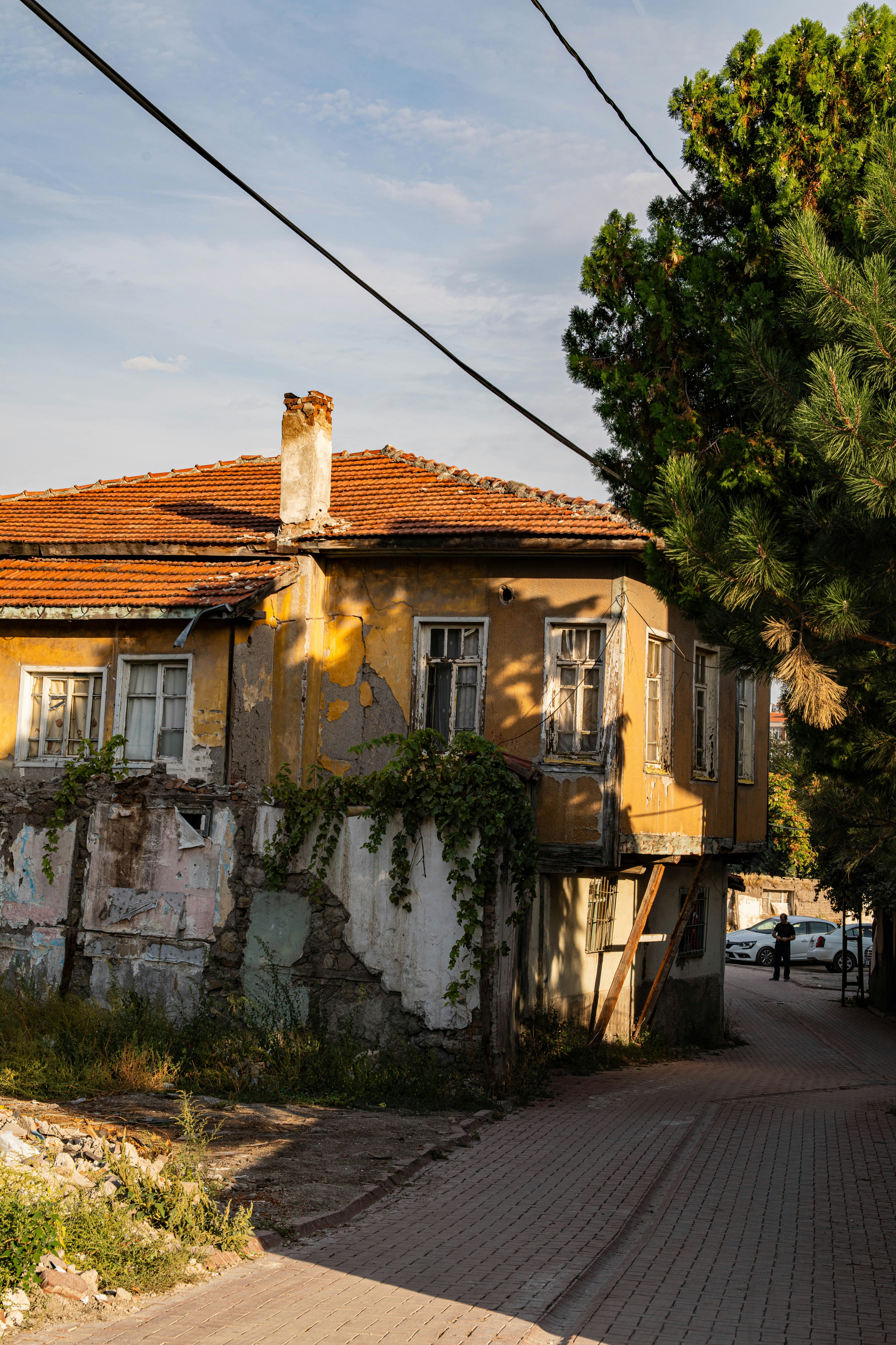 Sunlit Decay: A Yellow House Beside a Quiet Path