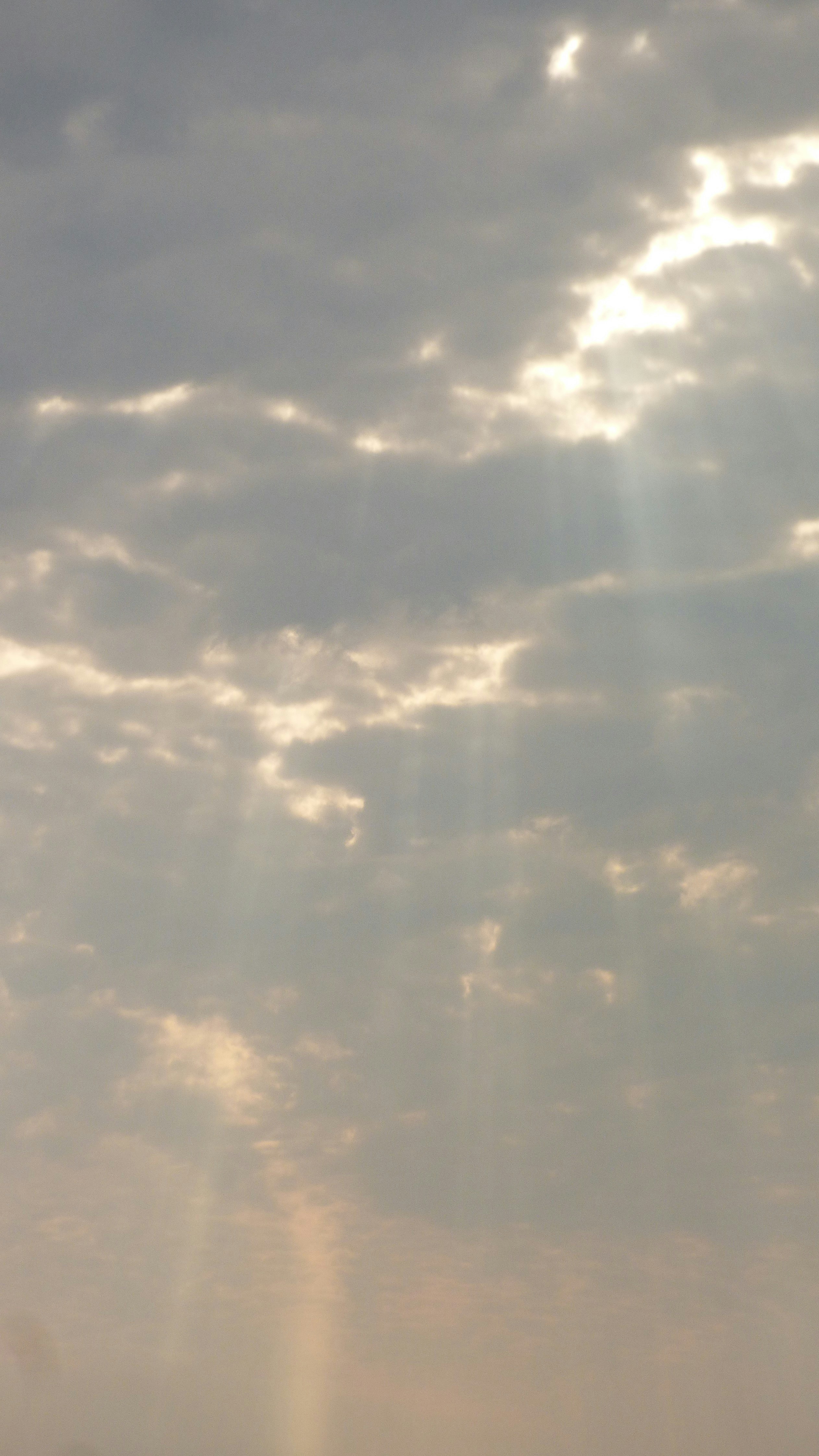 Sunbeams through Aerial Veil: Calm Sky Amid Soft Clouds