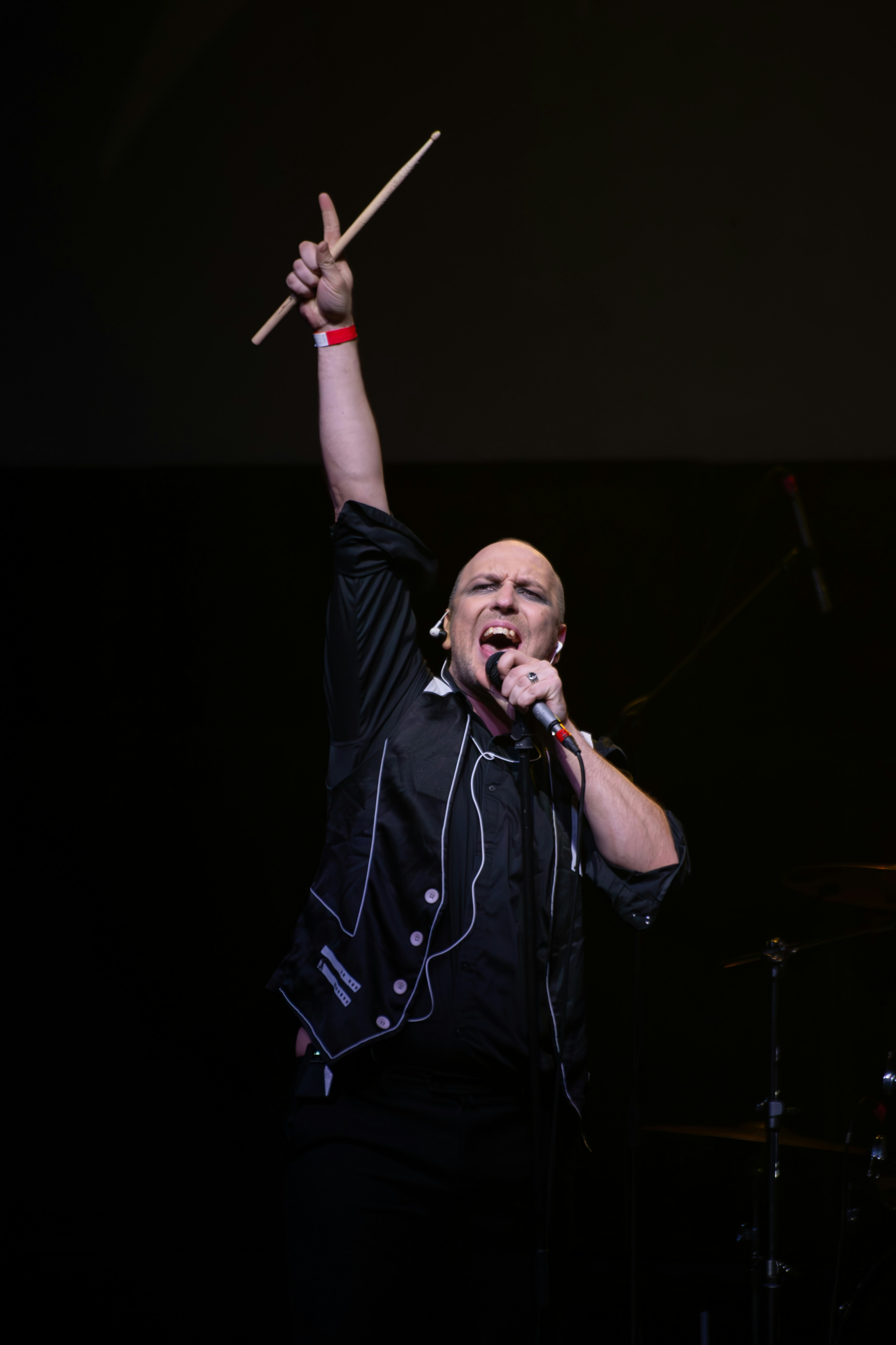 Mid-Riff Rally: The Singer’s Salute with Drumsticks Raised