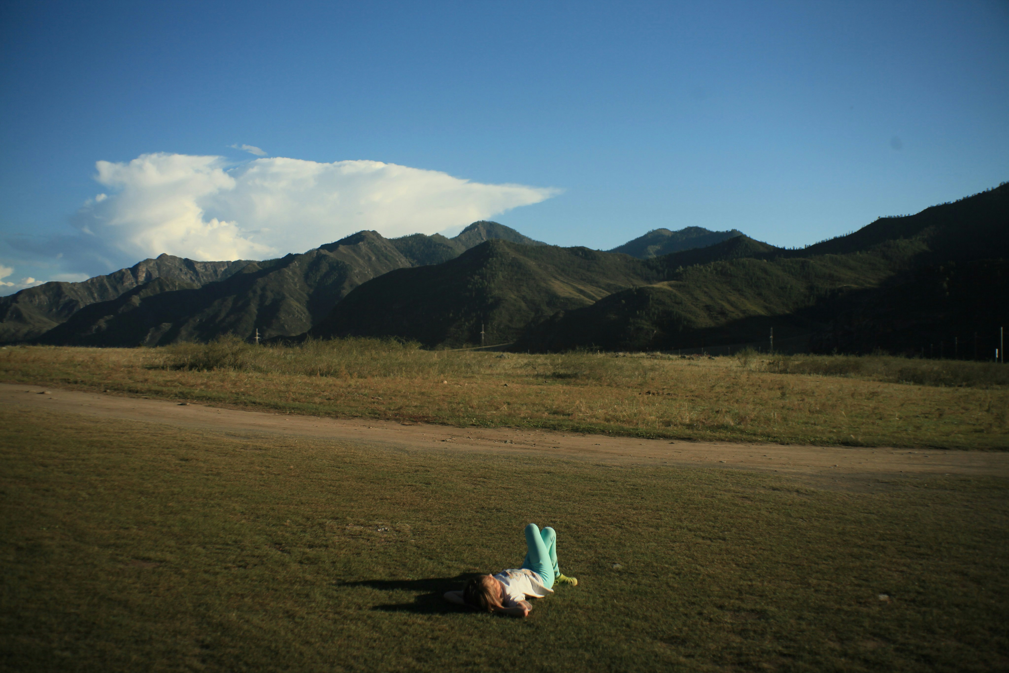 Downed Dandelion: A Lone Figure Resting in Riverbend Grass