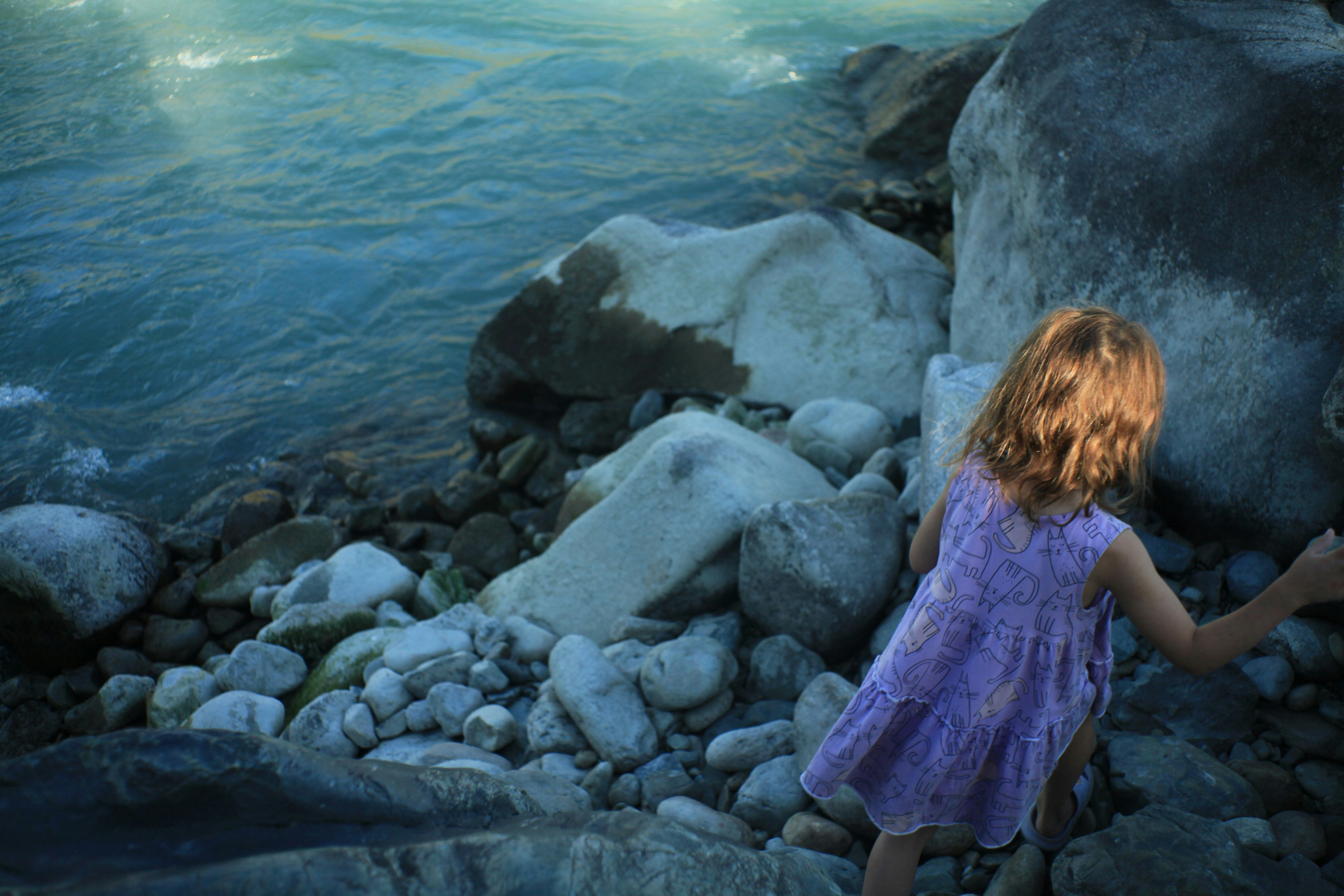 Rocky shoreline embrace: a child hand in hand along the water