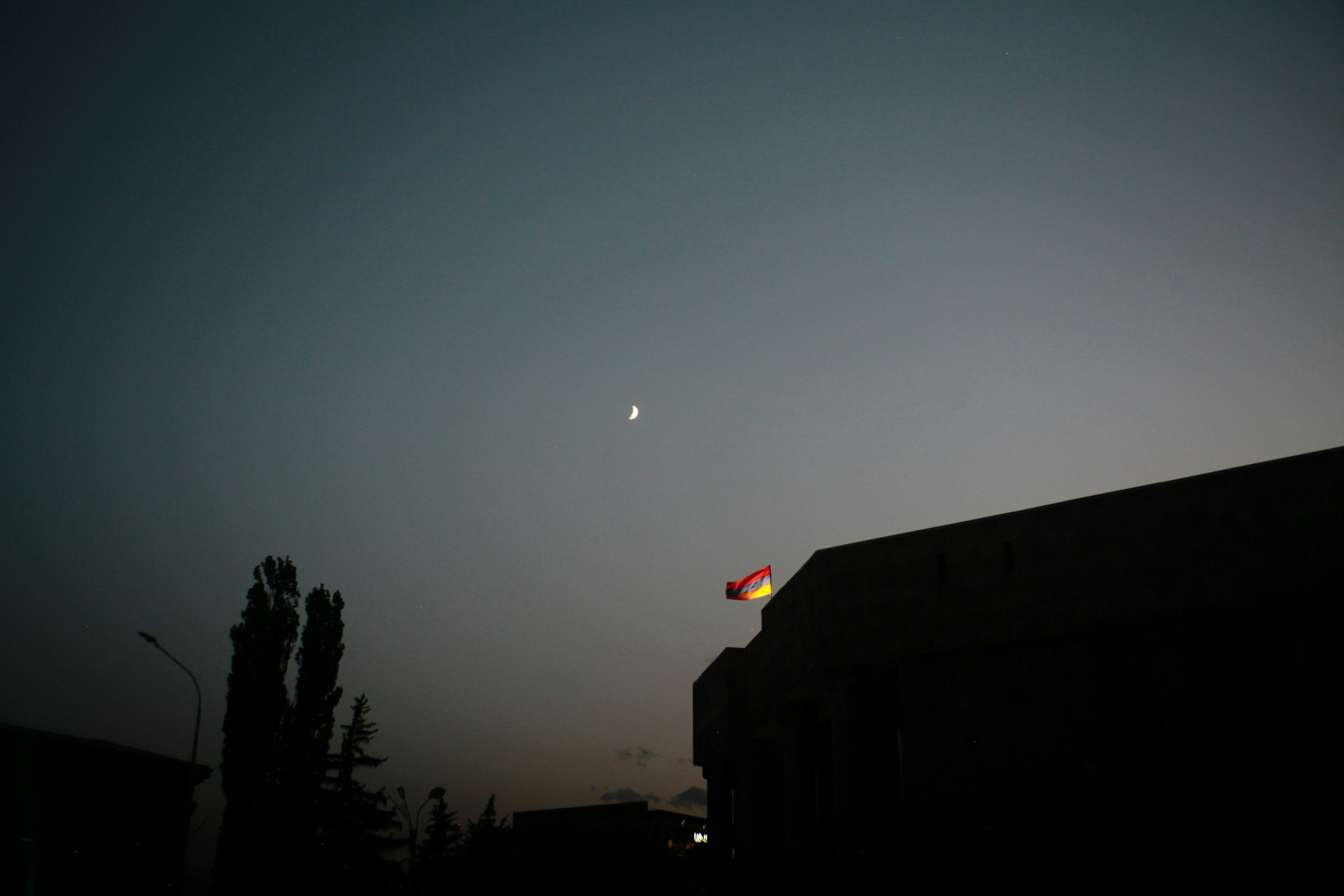 Dusk at the Corner: A Lone Crescent above a Quiet Building