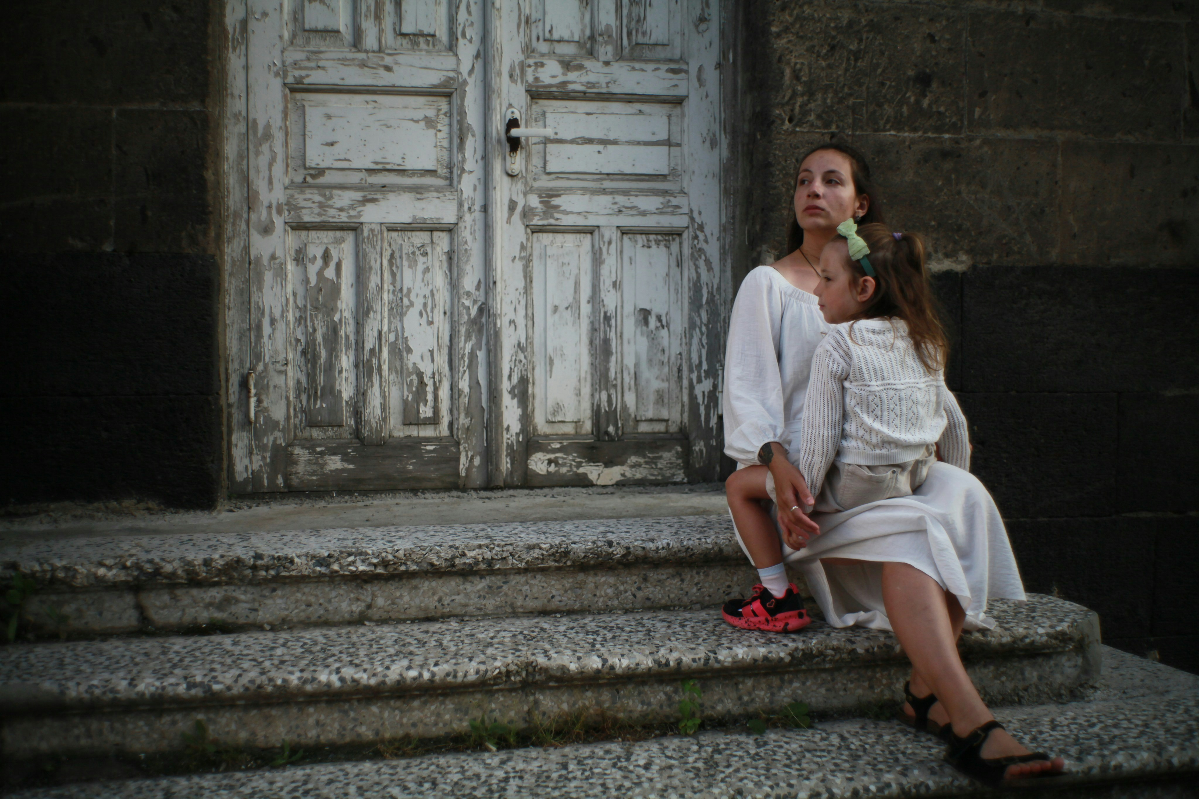 Two sisters on weathered steps, a quiet moment by the old door