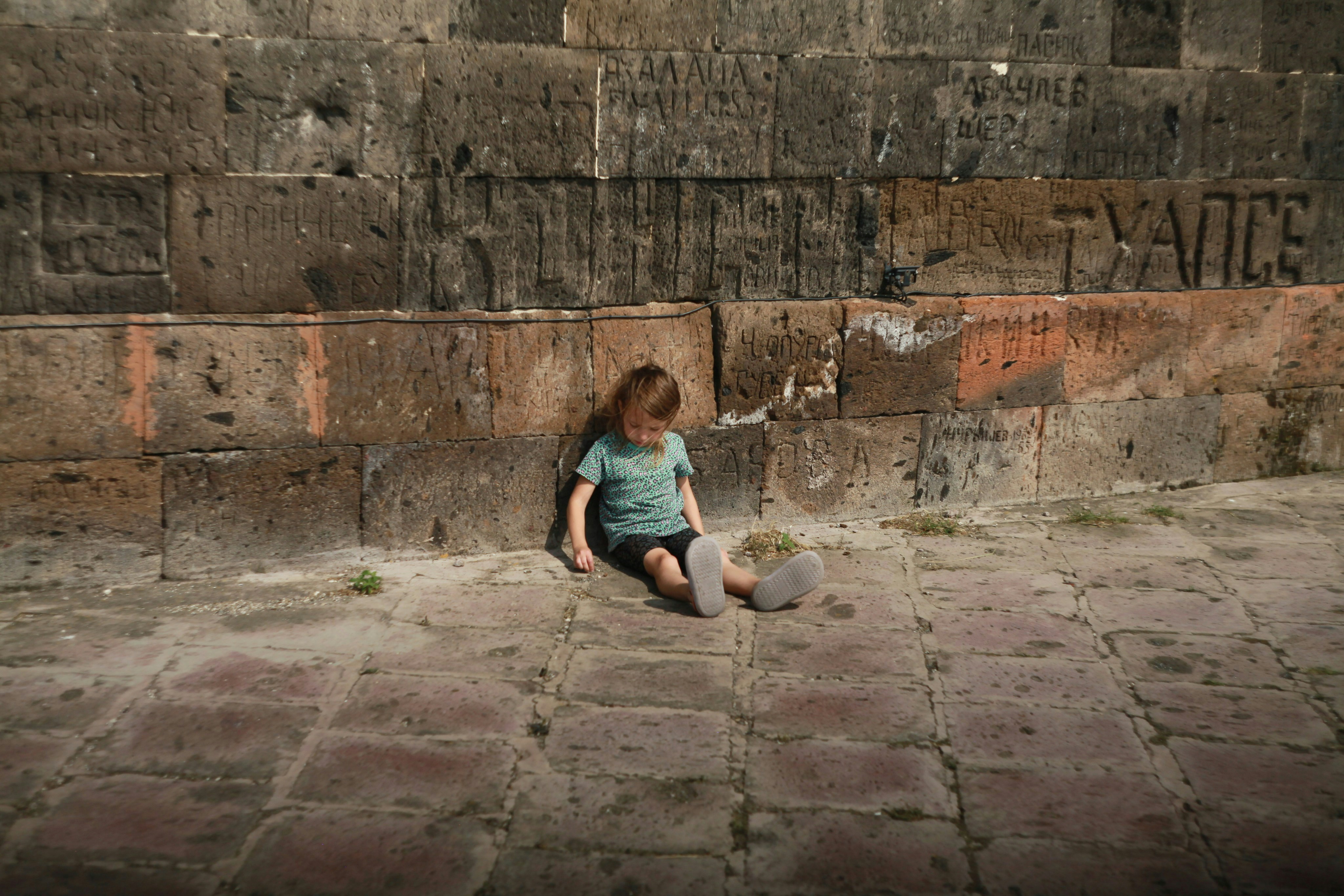 Child in a Quiet Corner: A Pause by the Weathered Wall
