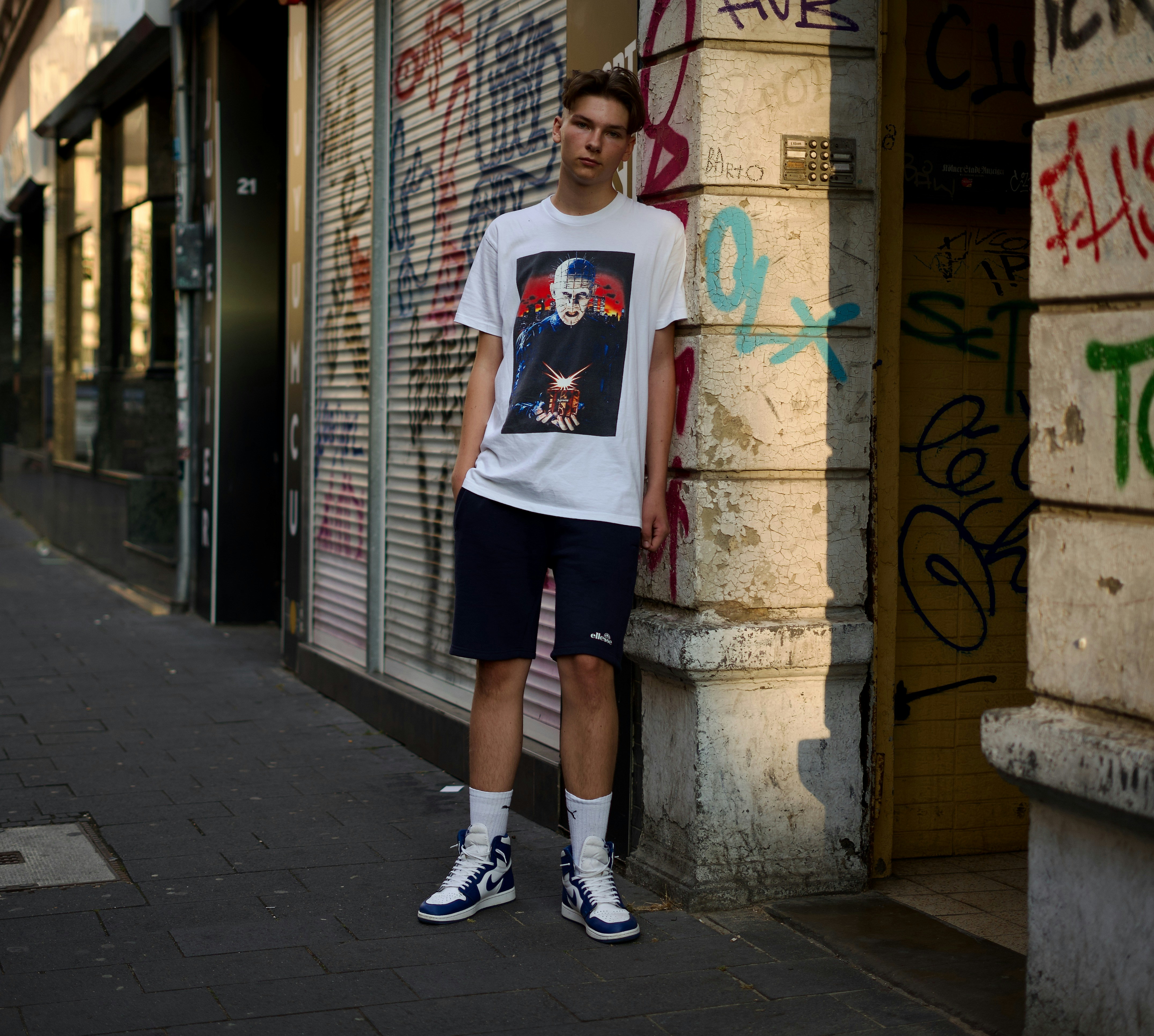 Against the Graffiti Wall: A Casual Stance by the Brick Corner