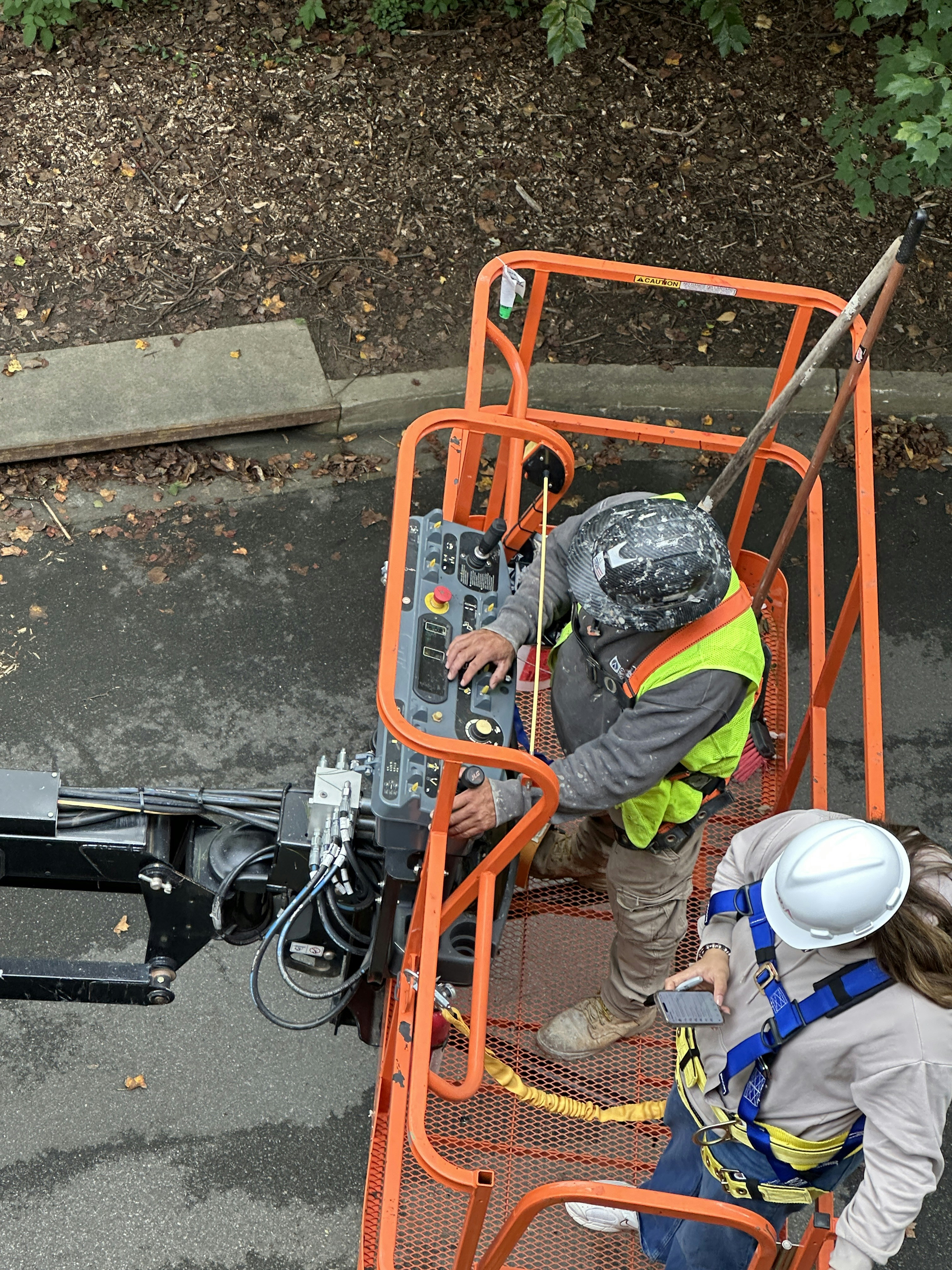High-Altitude Utility: Operators in an Orange Cage at Ground-Level