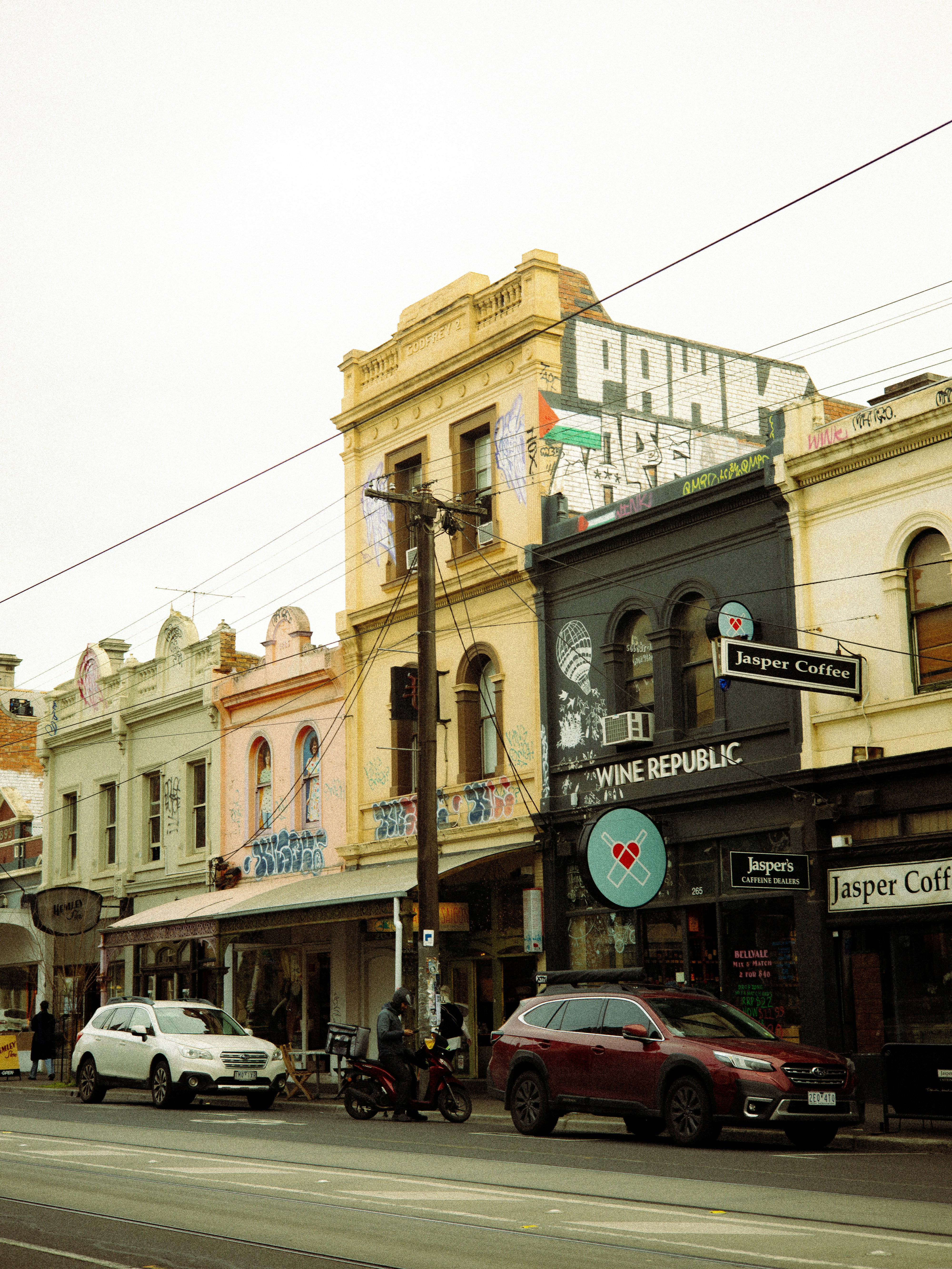 A row of colorful storefronts under a weathered urban skyline