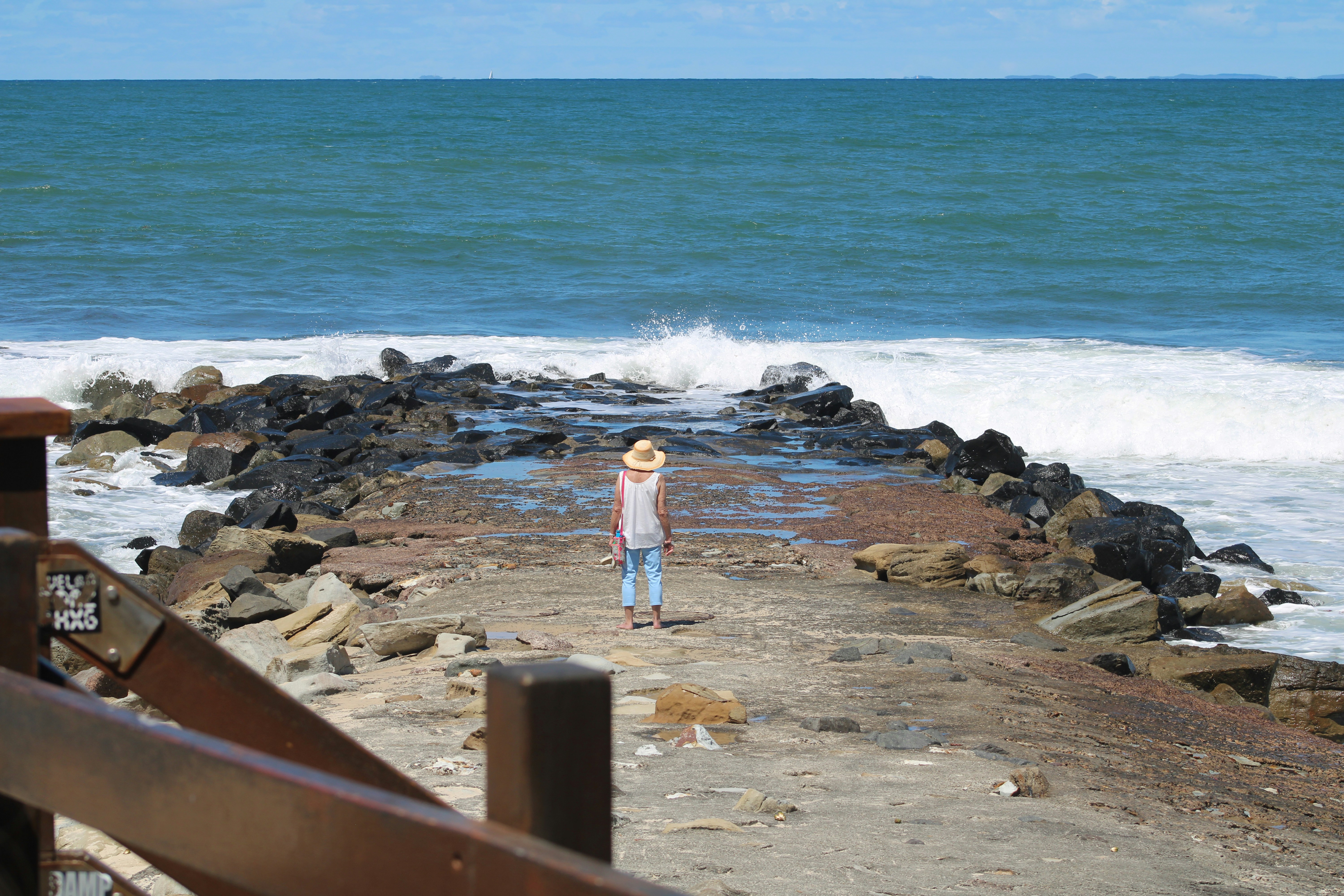 solitary hat and sunlit path: a lone figure at the sea’s edge