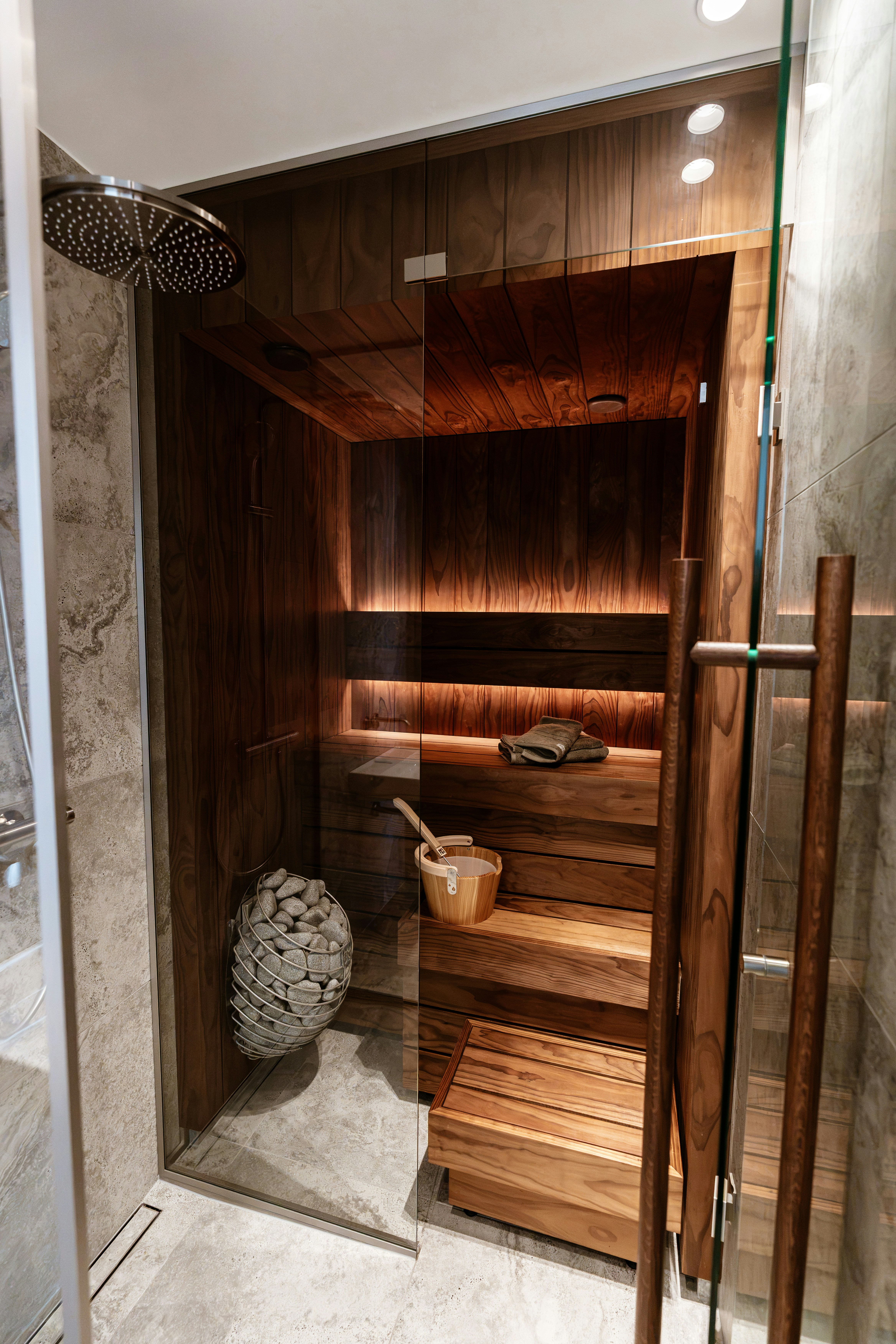 Warm Wooden Retreat: Glass-Encased Sauna with Ambient Lighting