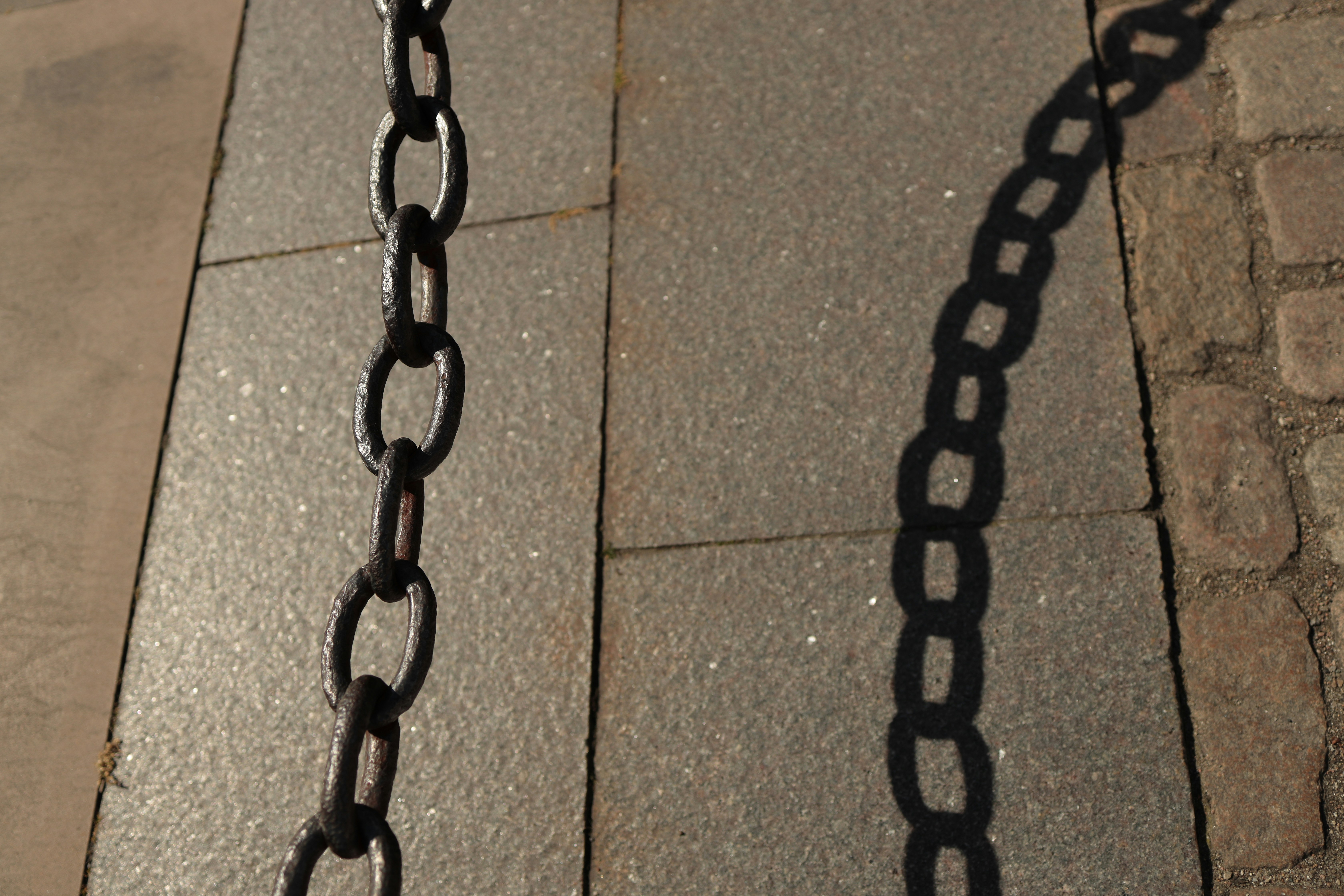 Shadowed Chains: A Quiet Path Along Sunlit Pavers