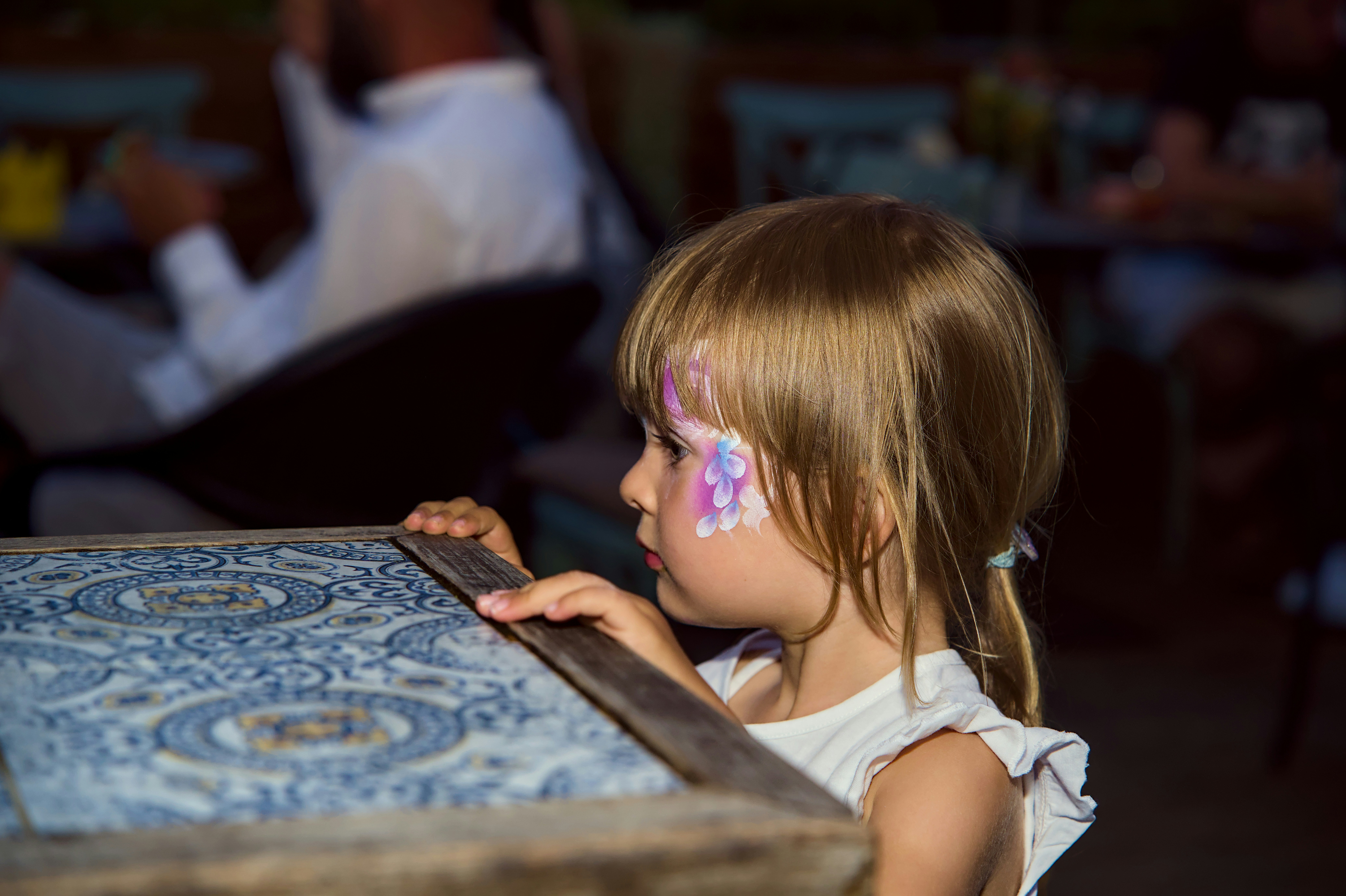 Girl with Flower Face Paint at a Table Edge