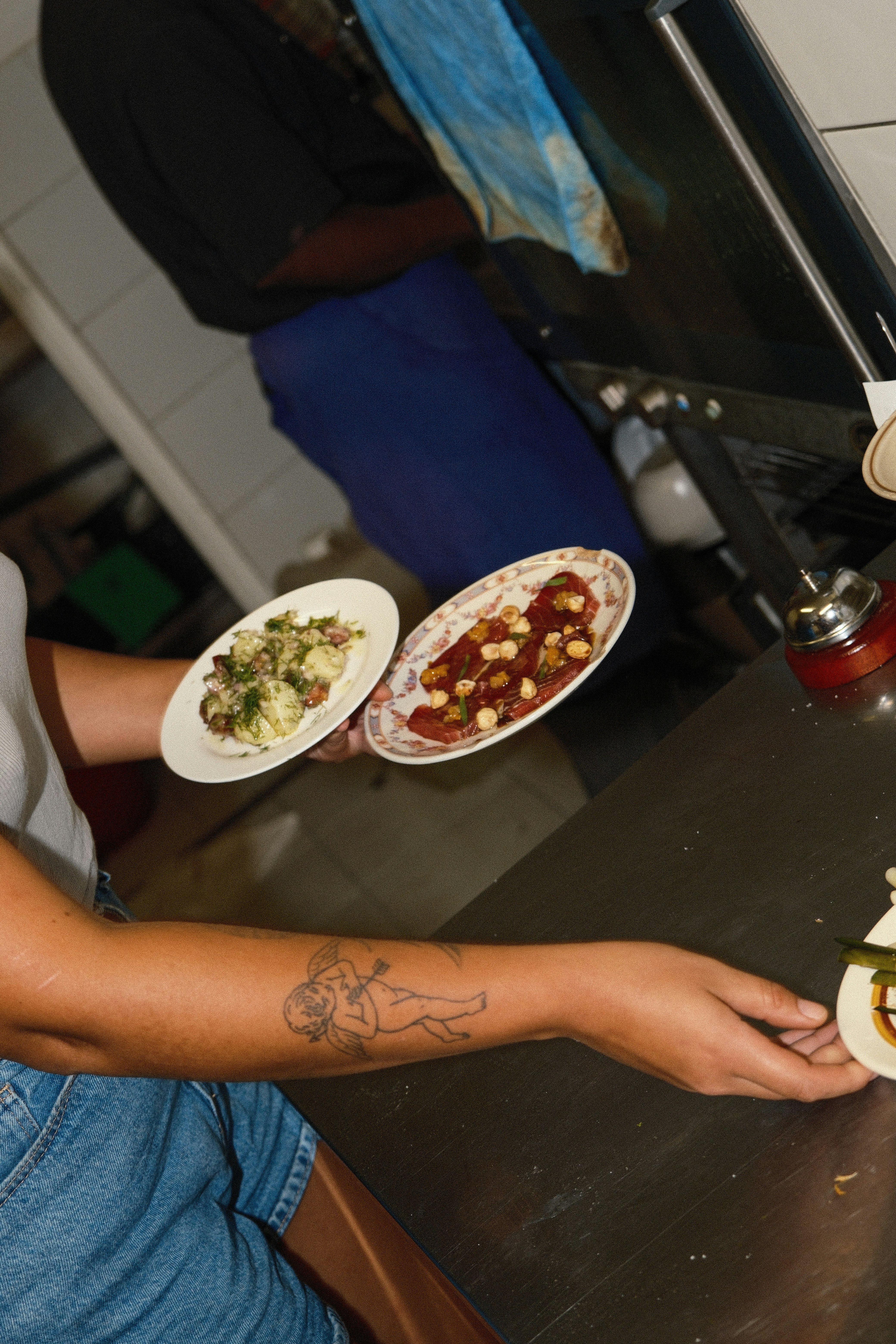 Plateau of Plates: A Busy Kitchen Moment with Tattooed Arm in Frame