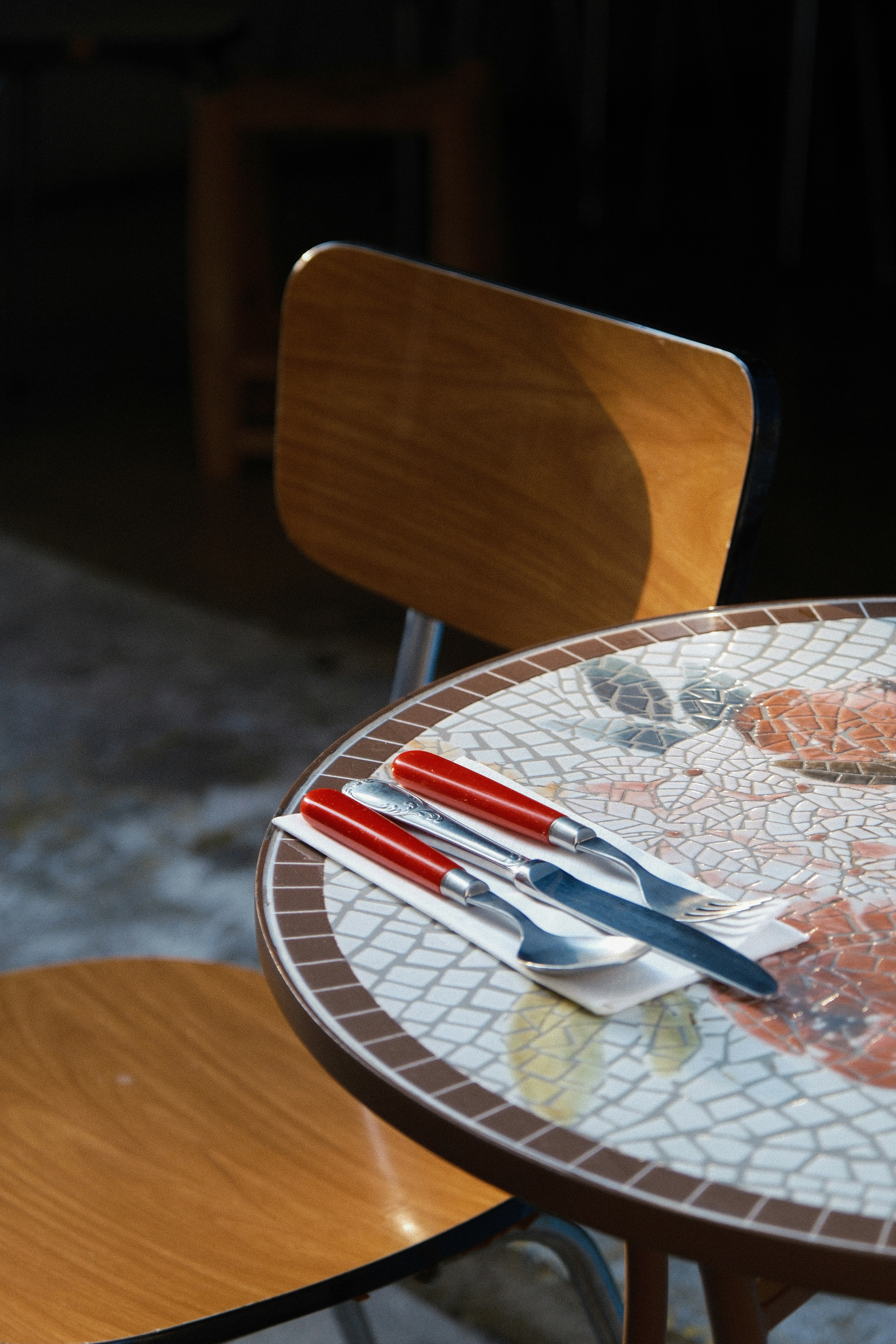 Still Life at the Café: Red-handled Cutlery on Mosaic Table