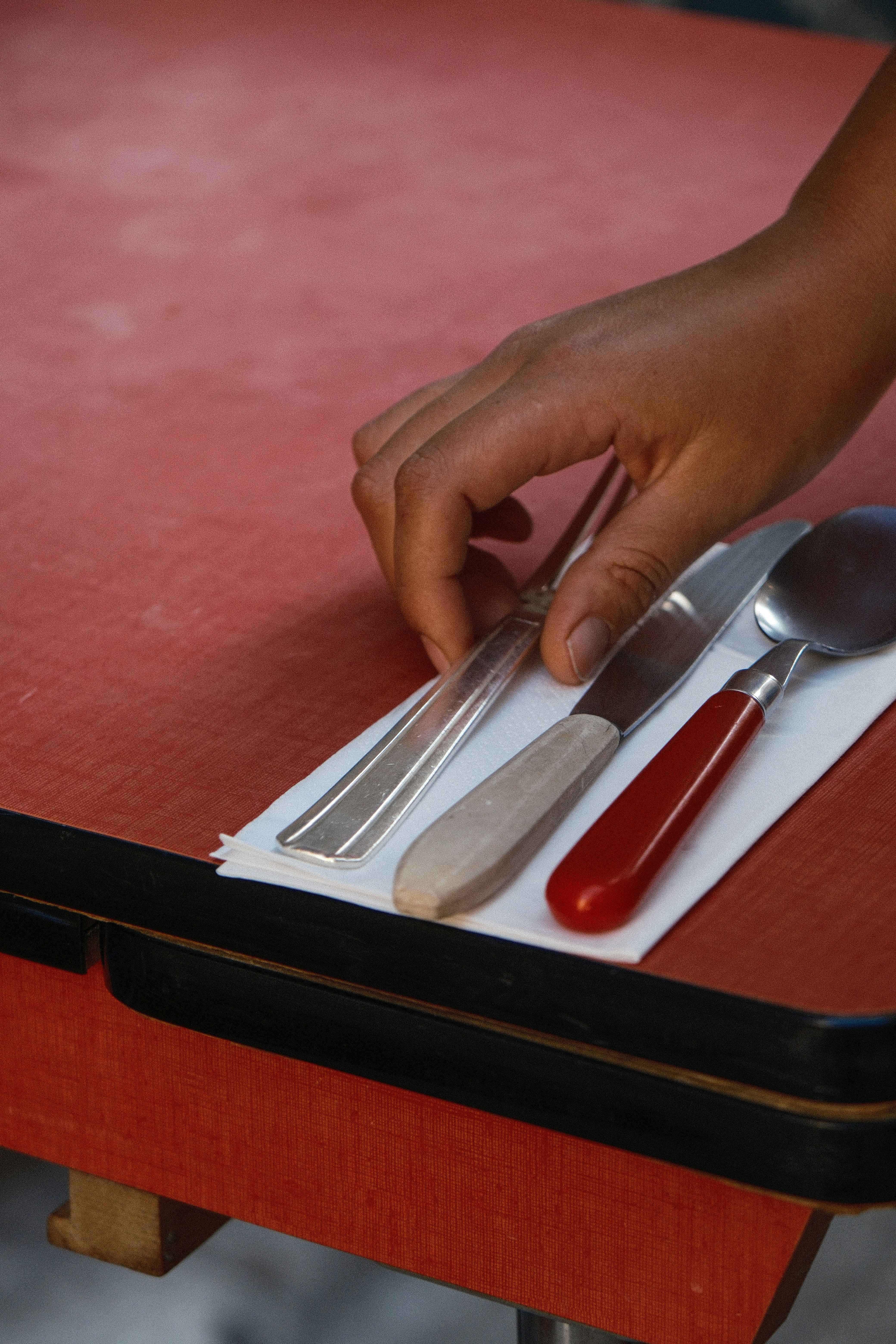 Hands at Work: A Moment of Precision with Cutlery on a Red-Cut Table