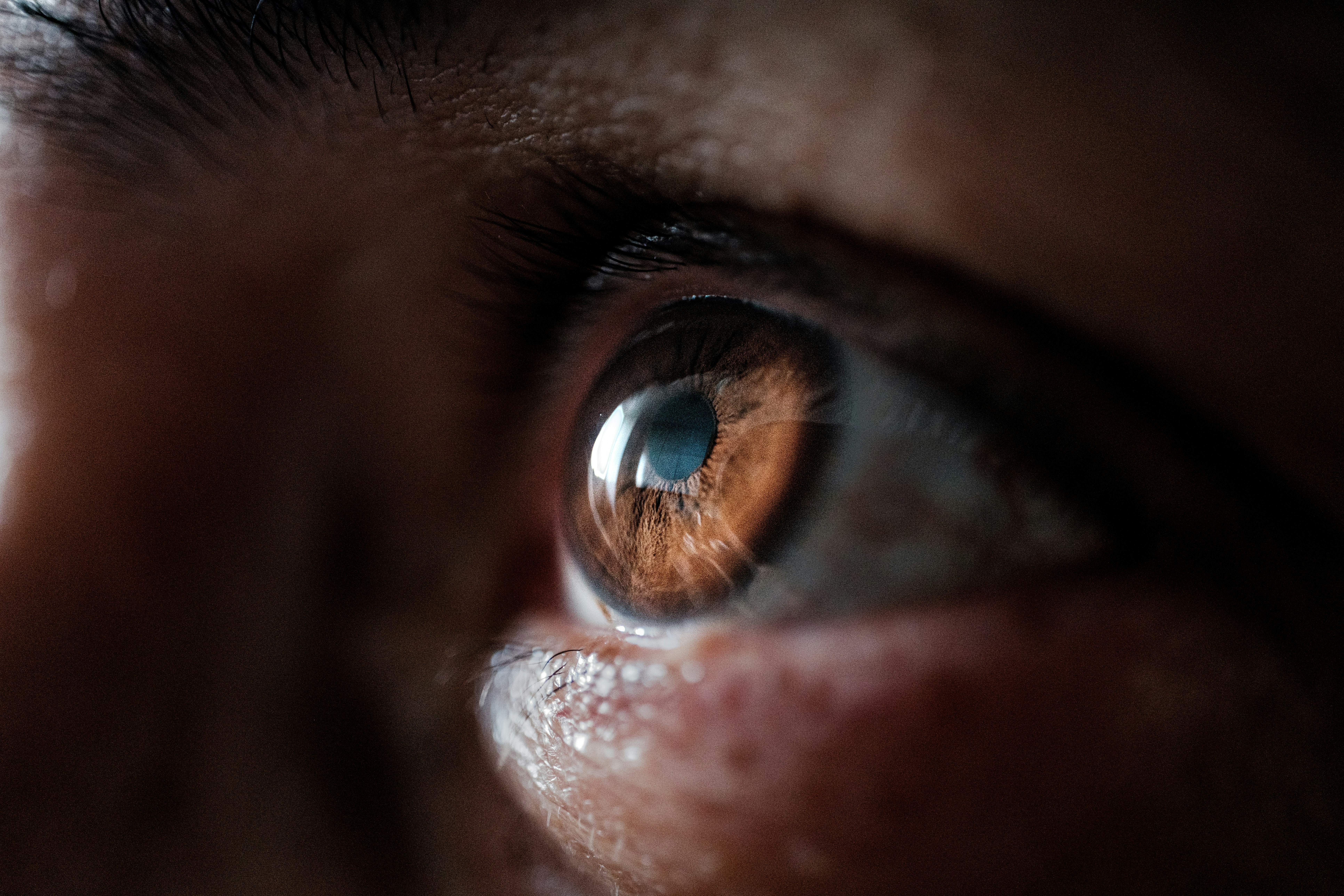 Close-up of a human eye with amber iris and visible texture, occupying most of the frame for an intimate portrait. This is a photographic capture, not a drawing or logo.