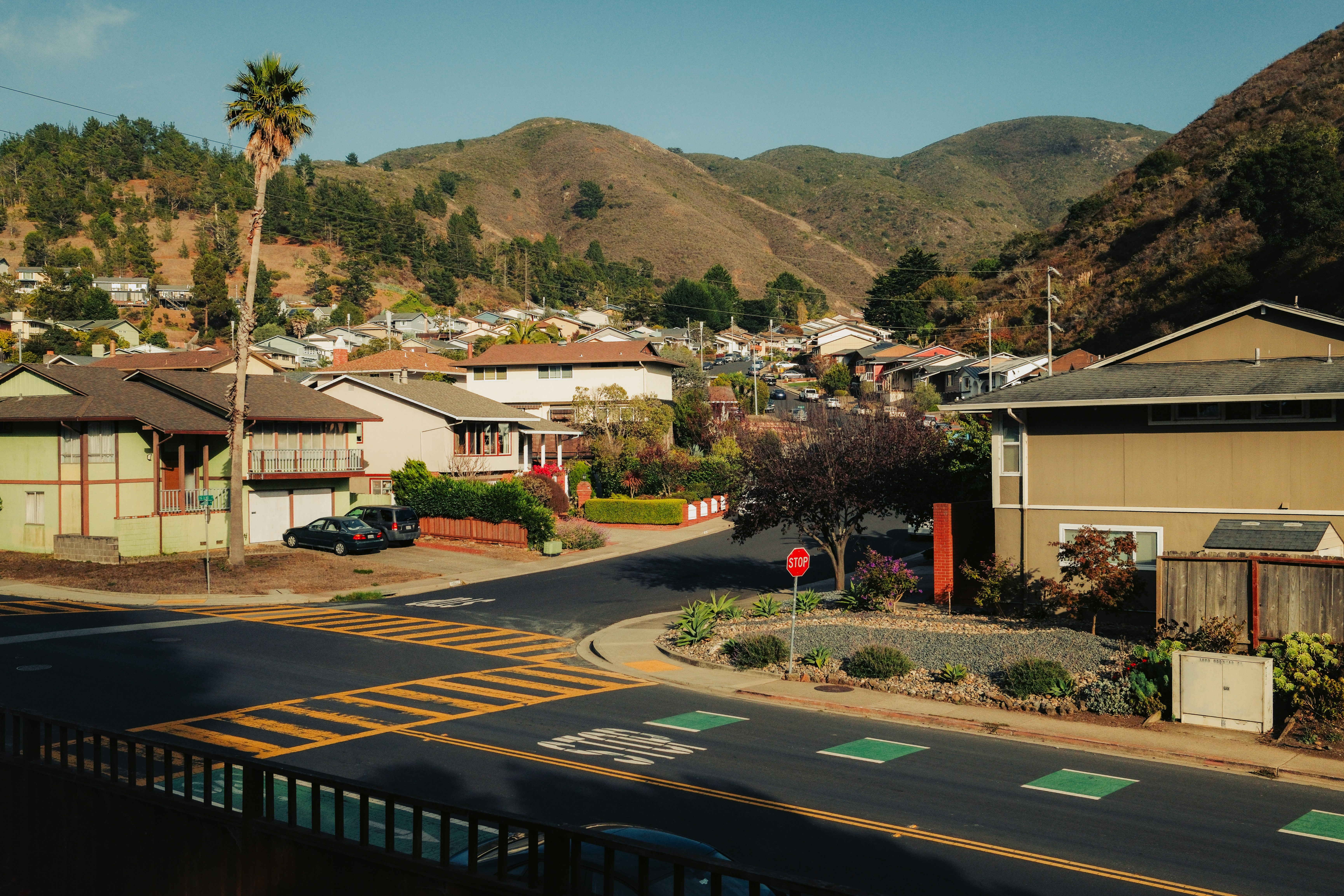 Sunlit suburban crossroads beneath gentle hills