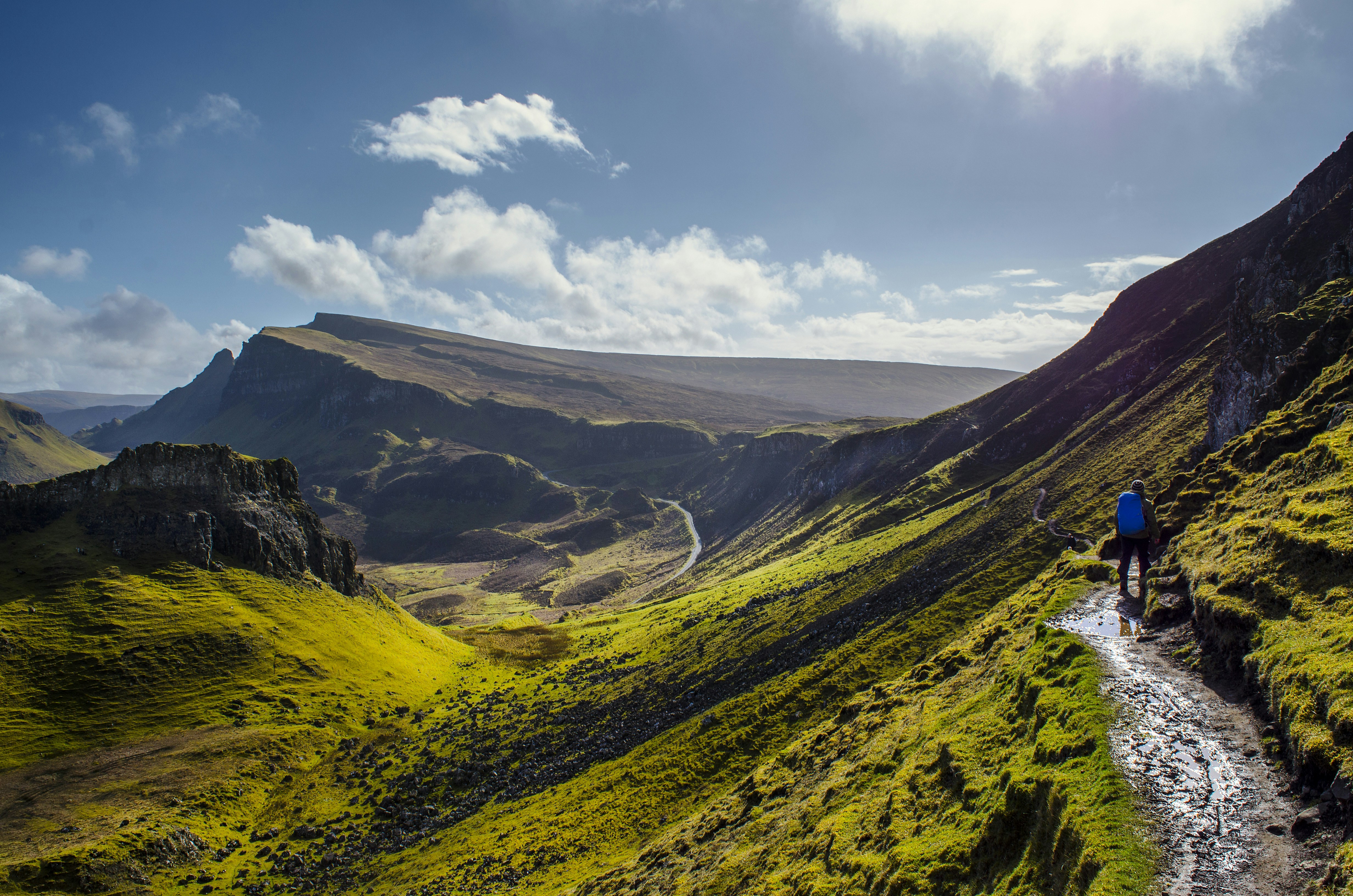 A Lone Hiker Traverses a Luminous Rift in Verdant Valleys
