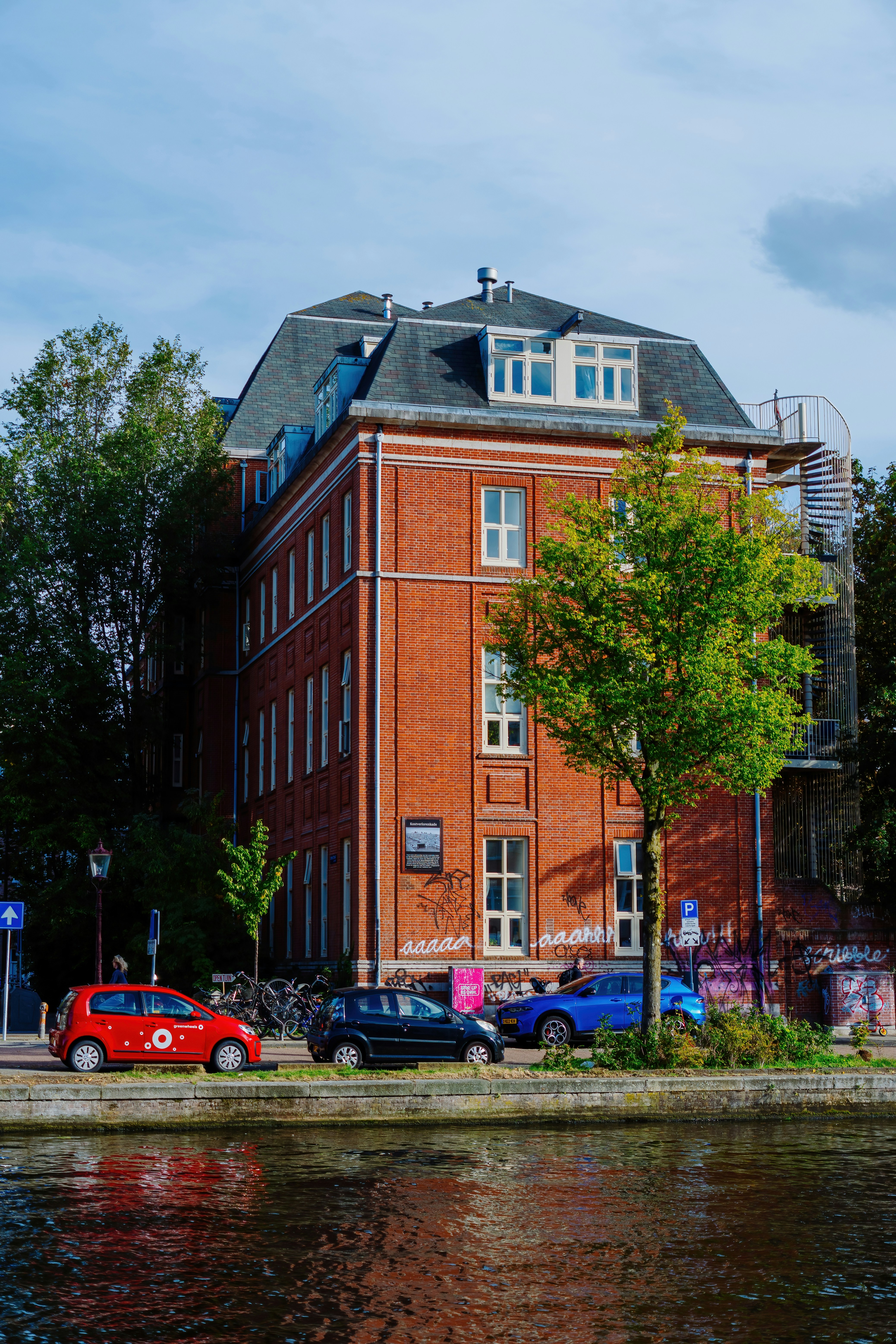 Brick-Red Waterfront Residence with Greenery and Canal Reflections