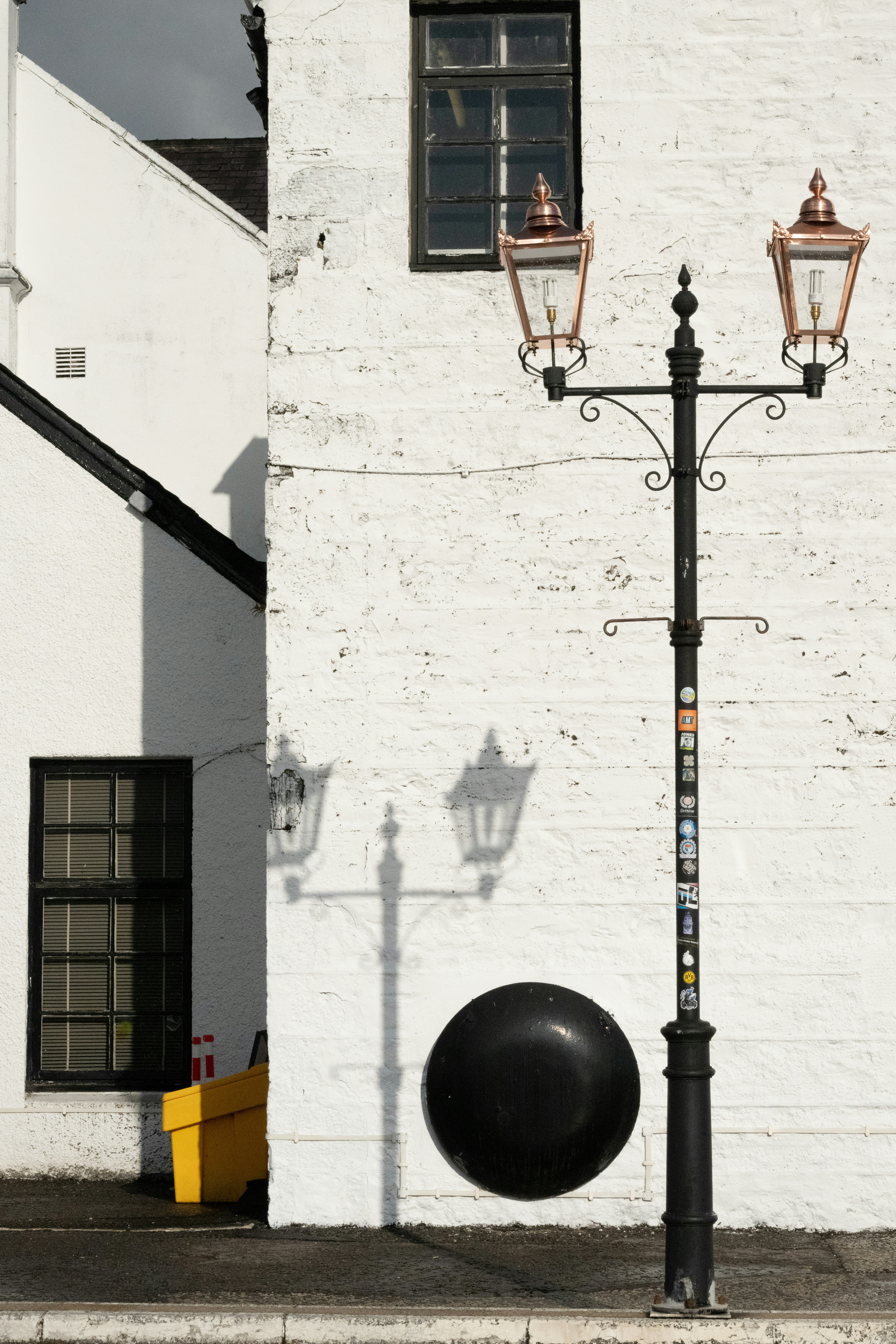 Shadowed Lanterns and a Black Sphere: Street Portrait of a White Wall