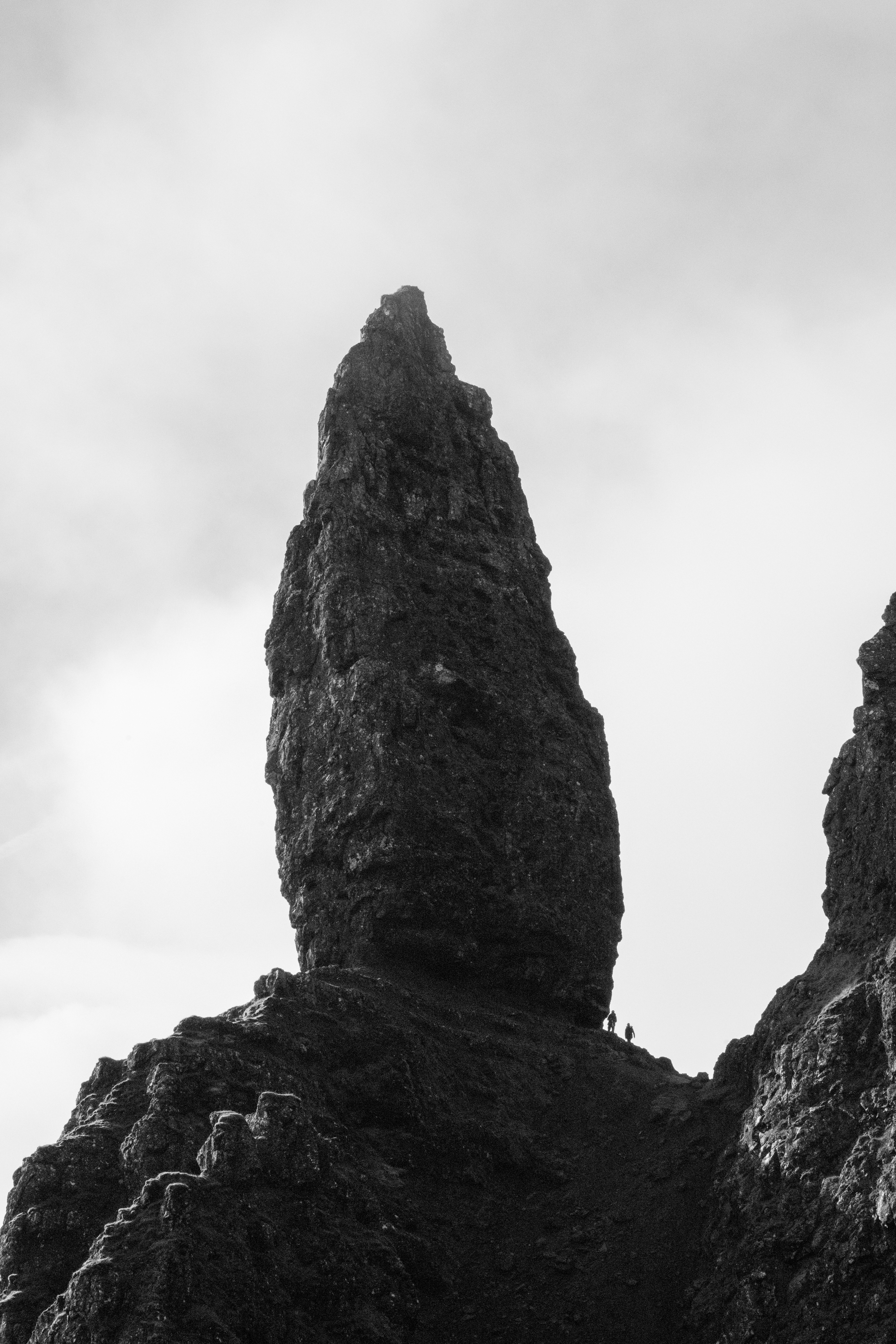 Stone Needle Against the Sky: A Lone Peak Rising from Dark Slopes