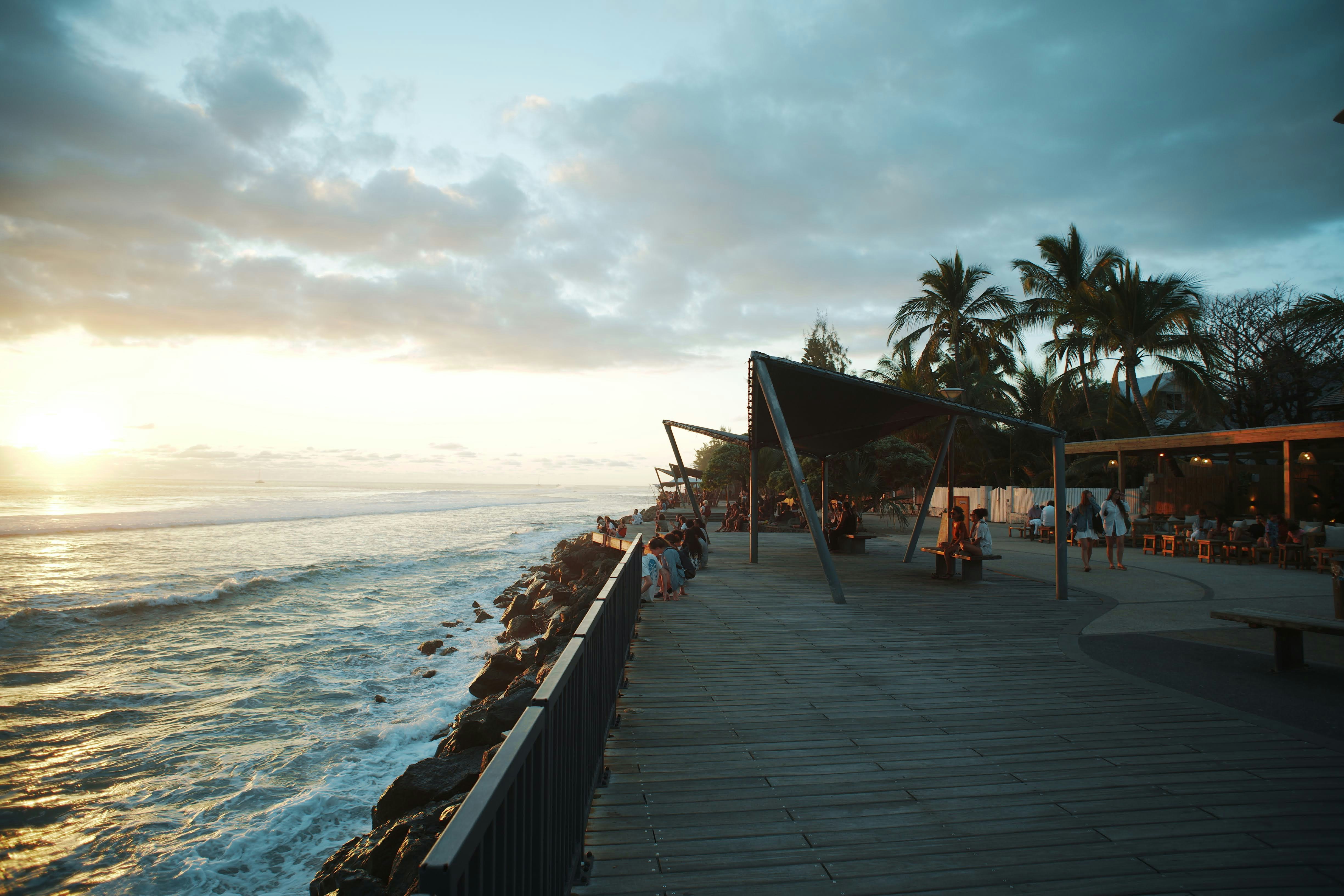 Sunset Promenade: Oceanfront Boardwalk with Silhouettes of Palm Trees