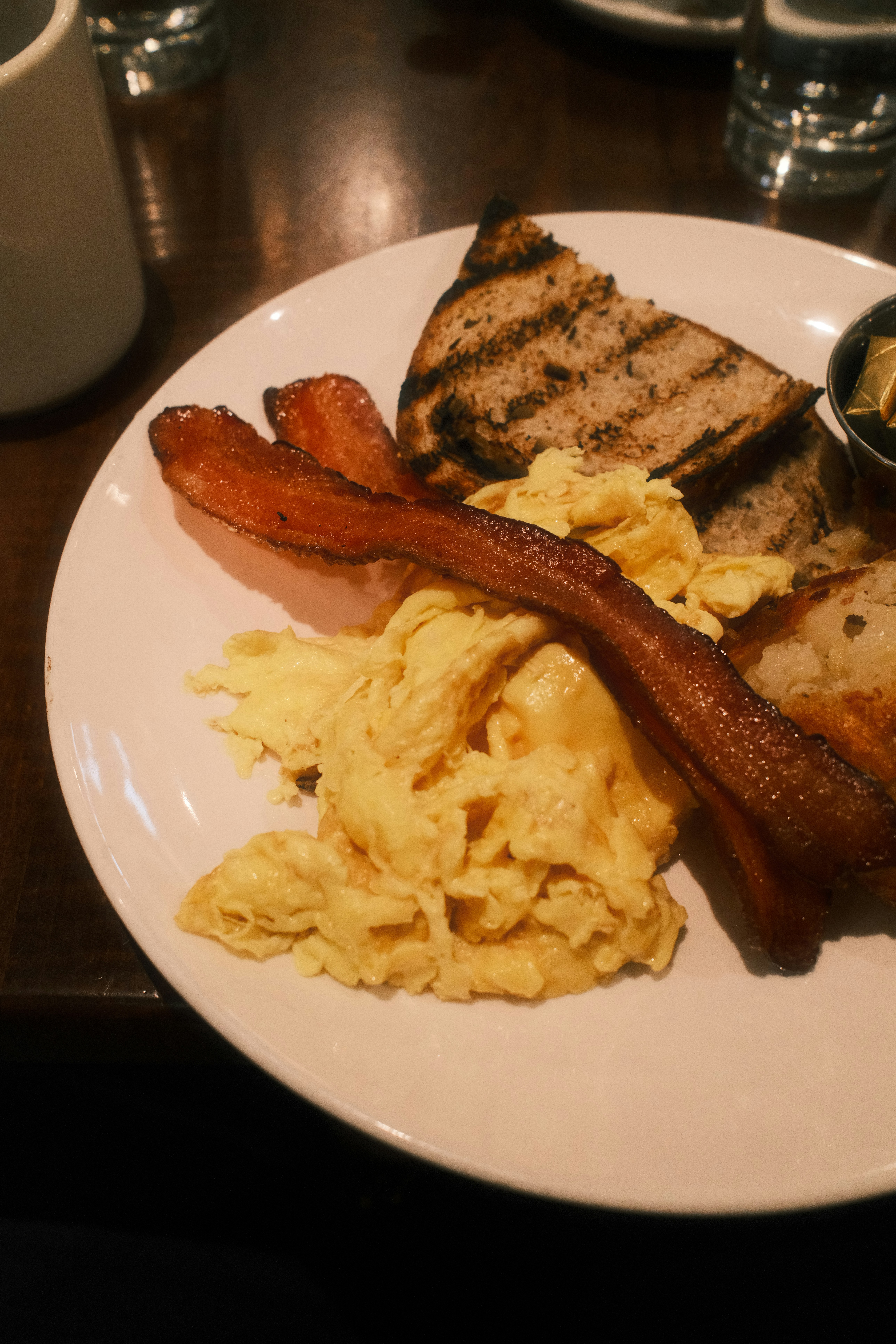 Savory Breakfast Triangle: Scrambled Eggs, Toast, and Crispy Bacon on a White Plate