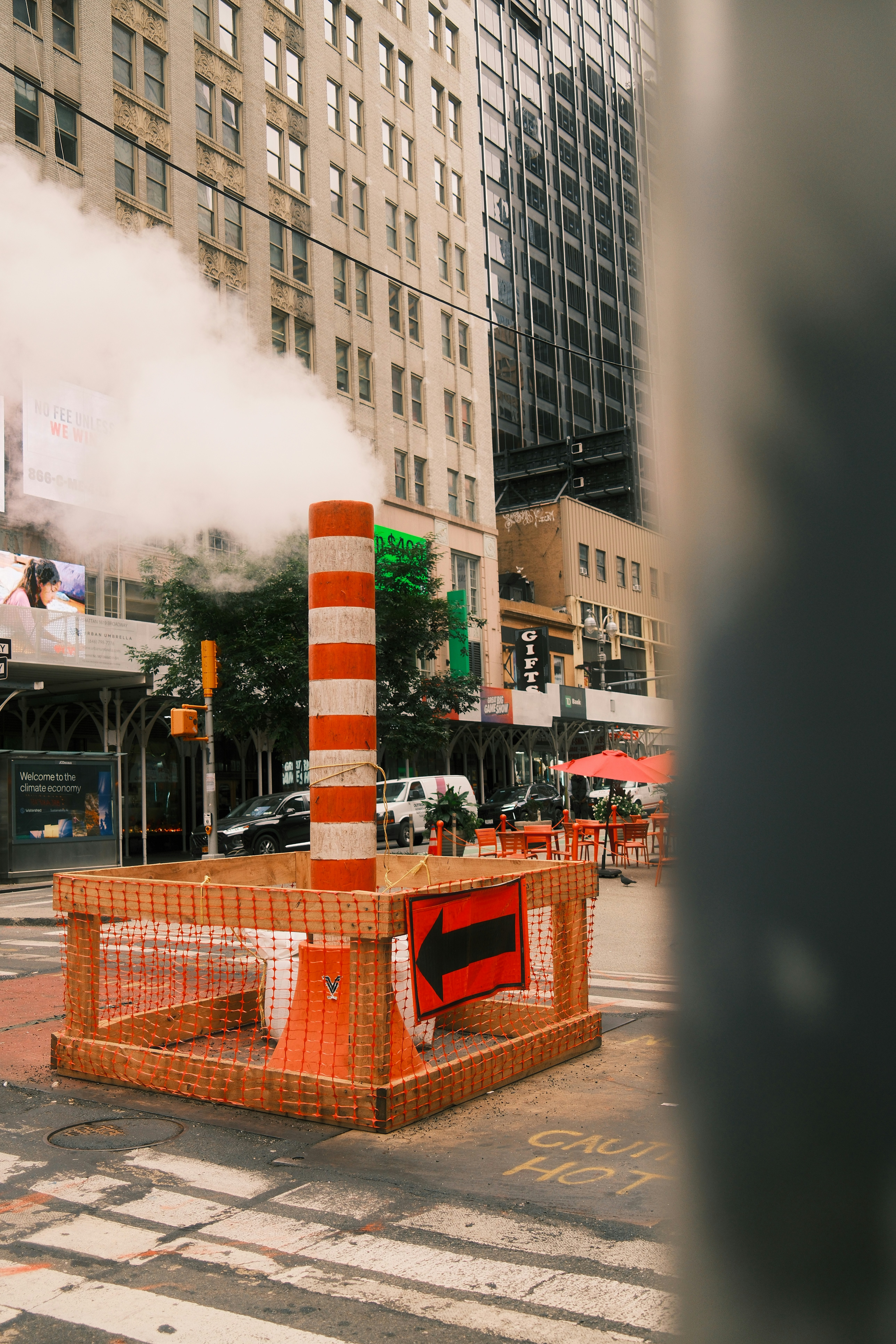 Steam rising from an orange and white striped pipe on a city street