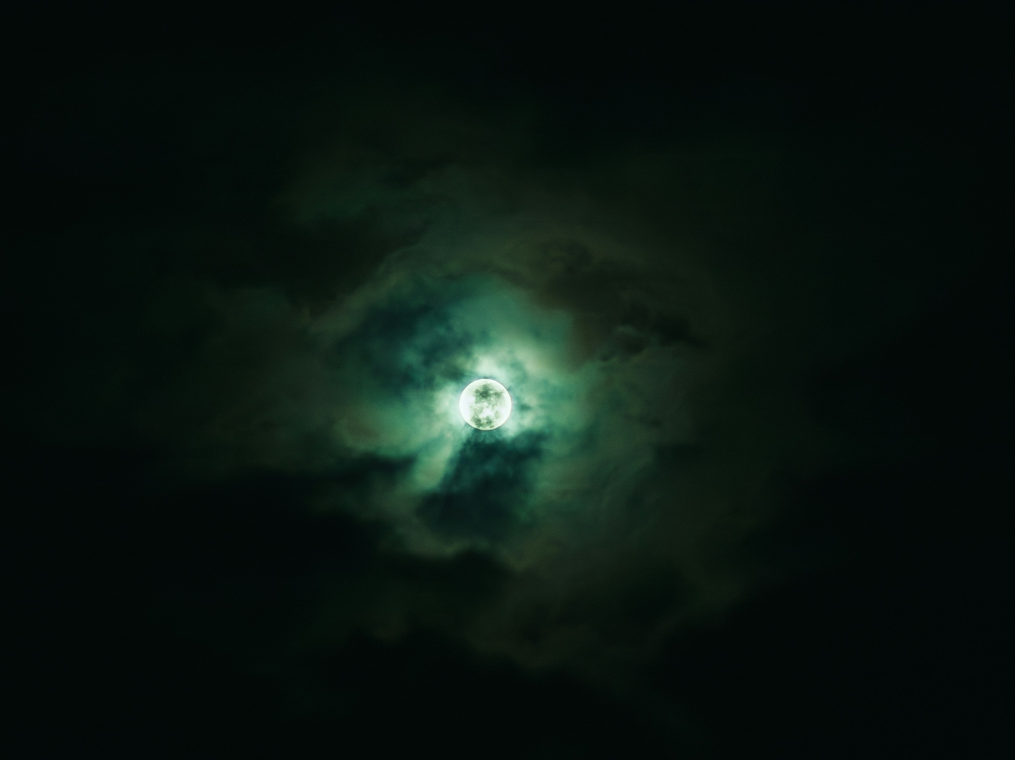 Moonlit Veil: The Haloing Circle Through Clouded Night