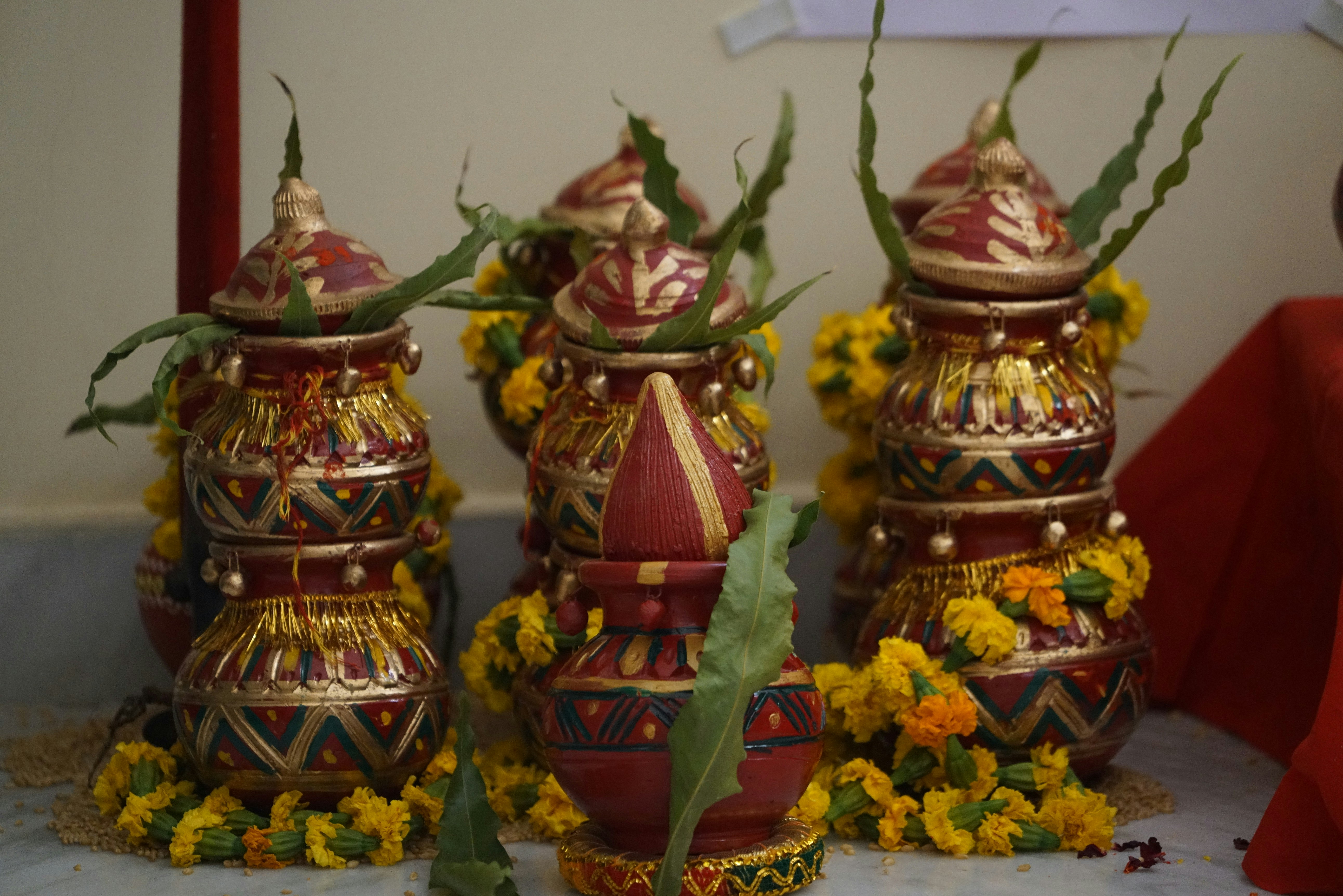 Refined ceremonial clay pots with intricate patterns and marigold garlands arranged on a shrine altar.