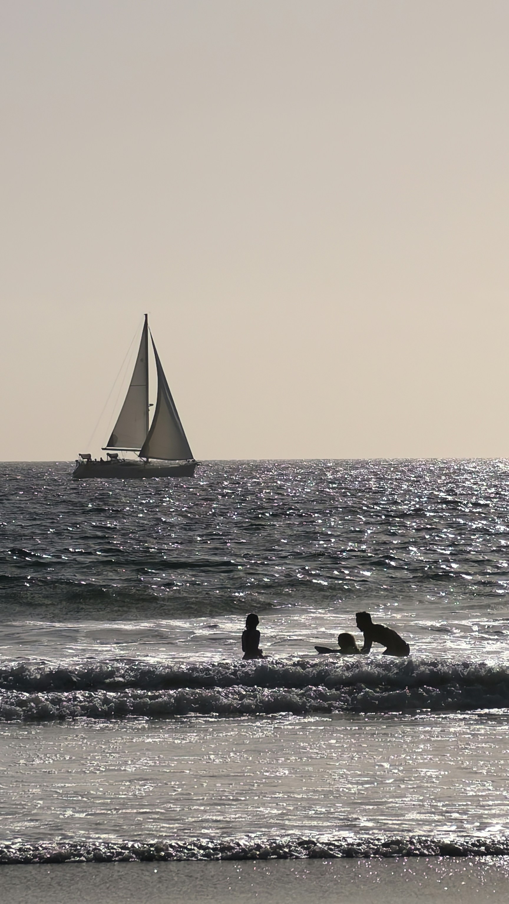 Sailboat lullaby: children at the shore in the late glow